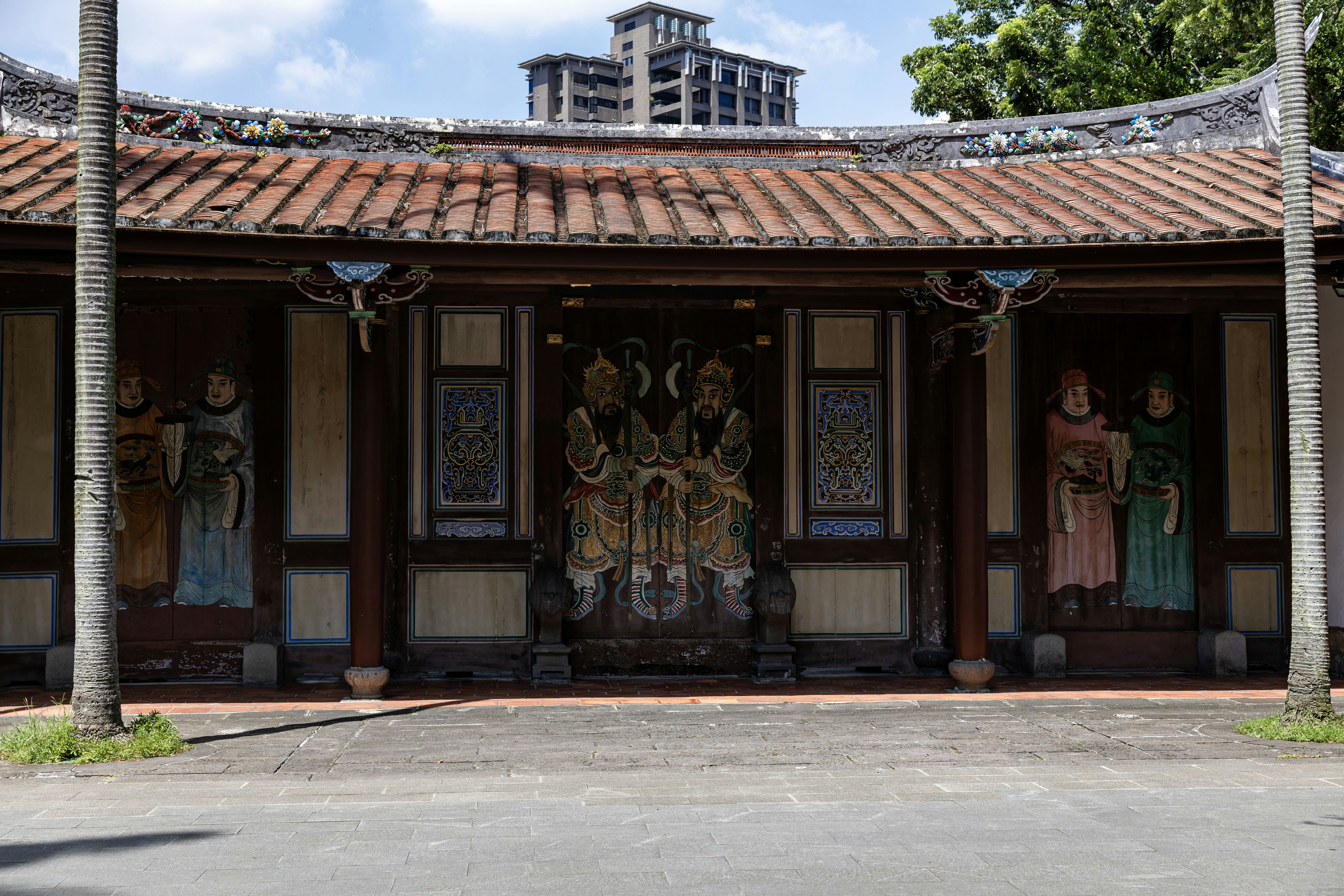 Central muraled facade of a traditional building framed by palm trunks