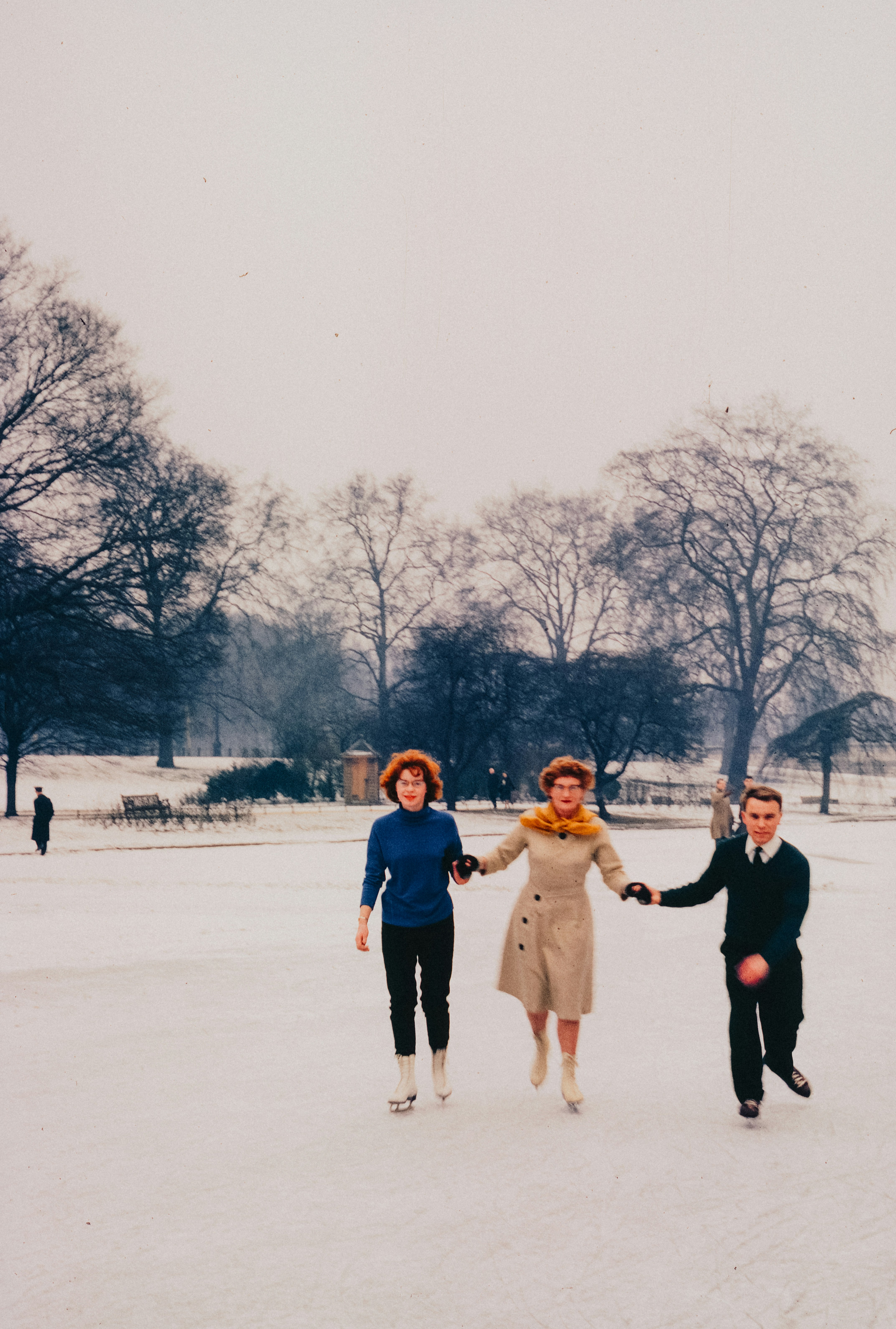 Three people ice skating on a frozen lake