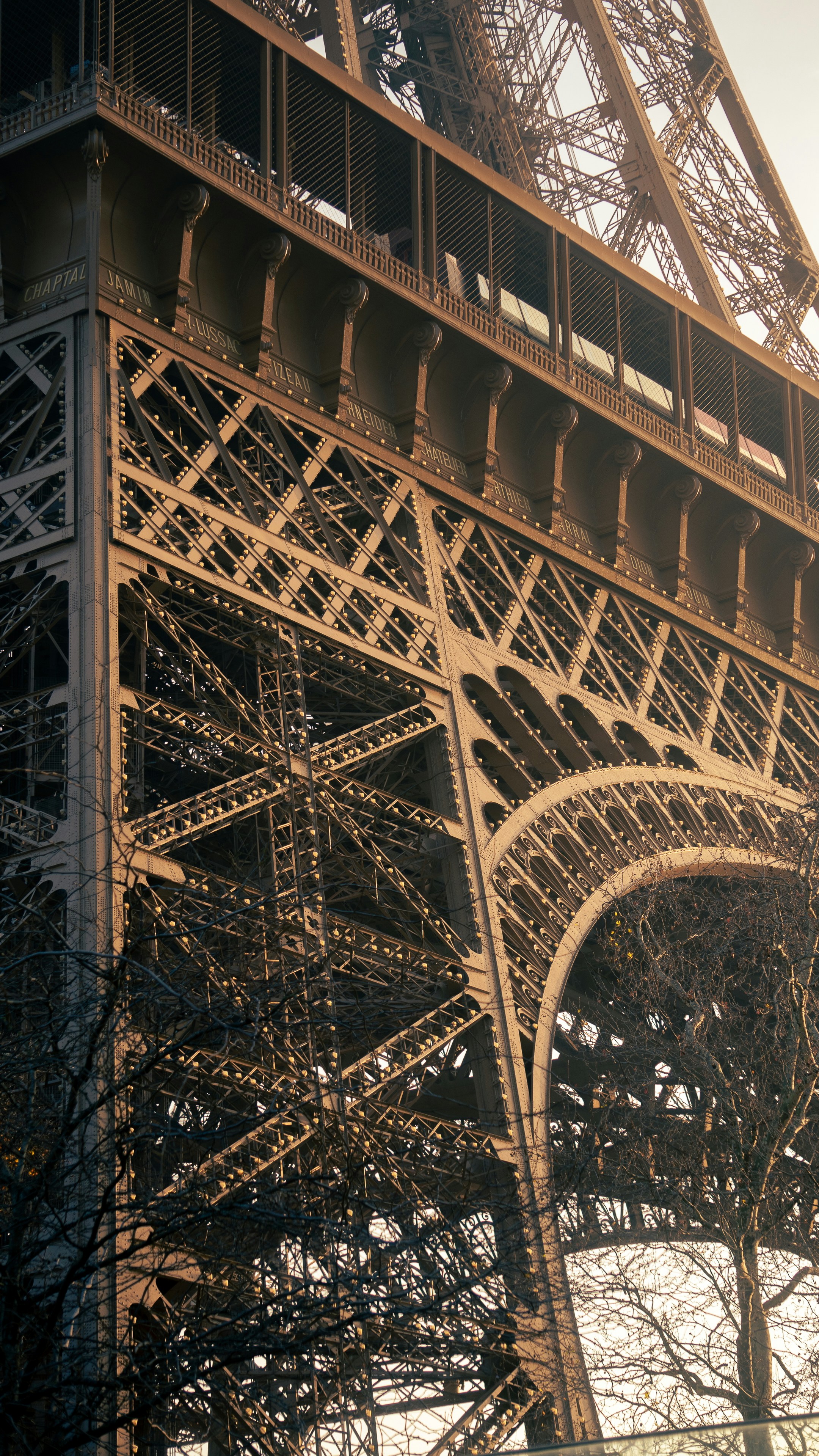 Sunlit Iron Lace: The Eiffel Tower's Curved Arch in Warm Light