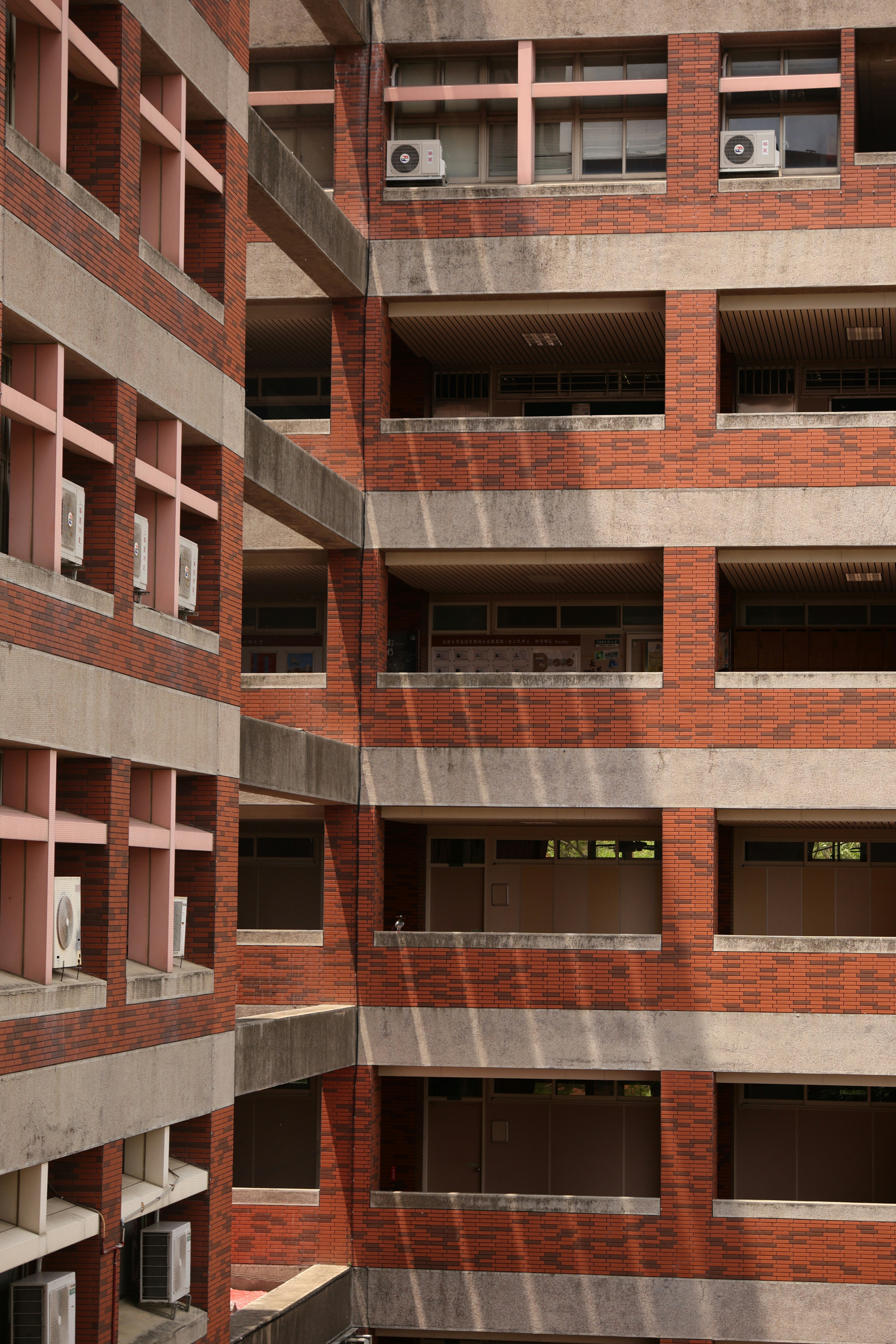 Red brick building with many windows and air conditioners