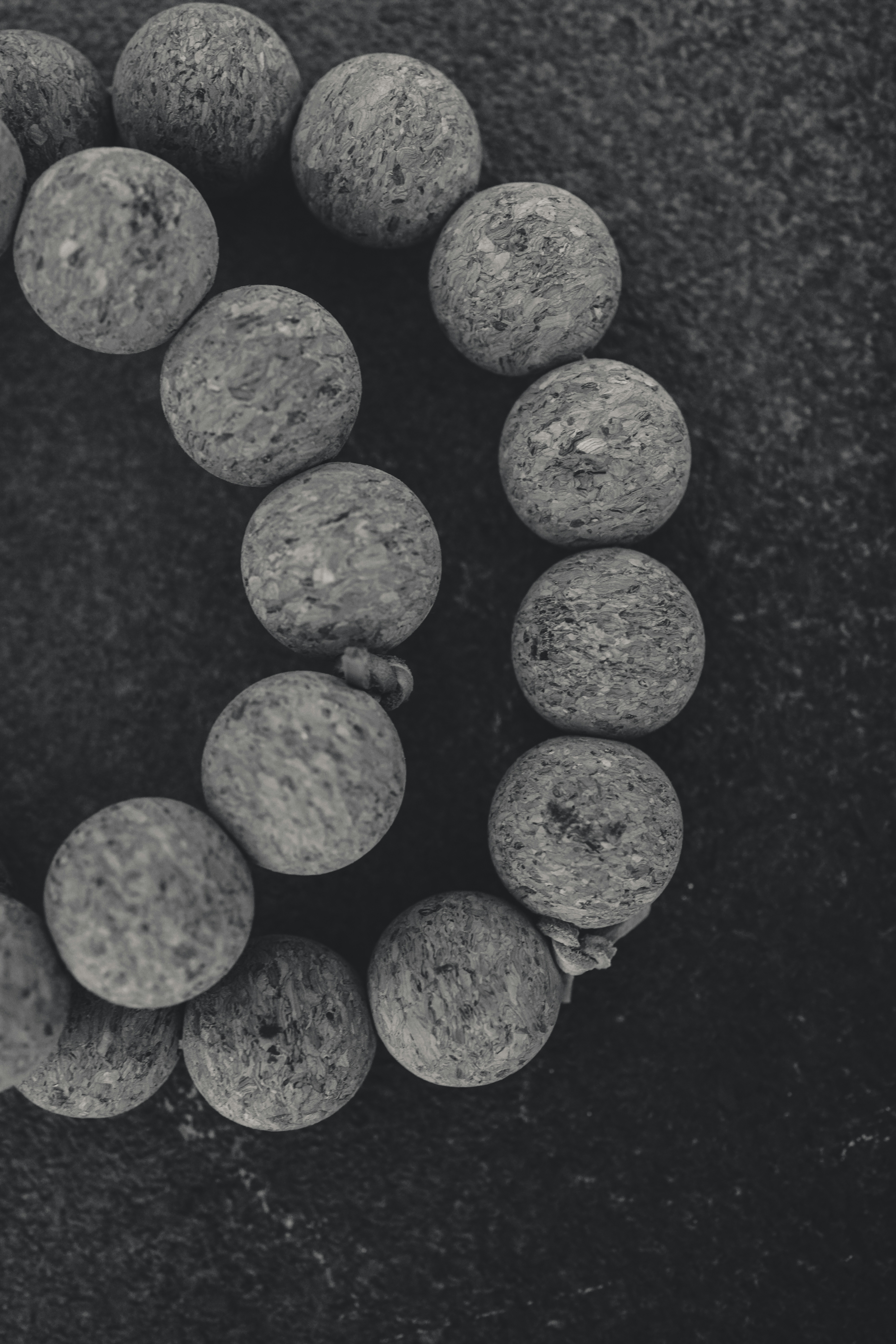 Close-up of a round cork bead bracelet in monochrome. The rough, natural texture and circular pattern create a minimal, graphic still life