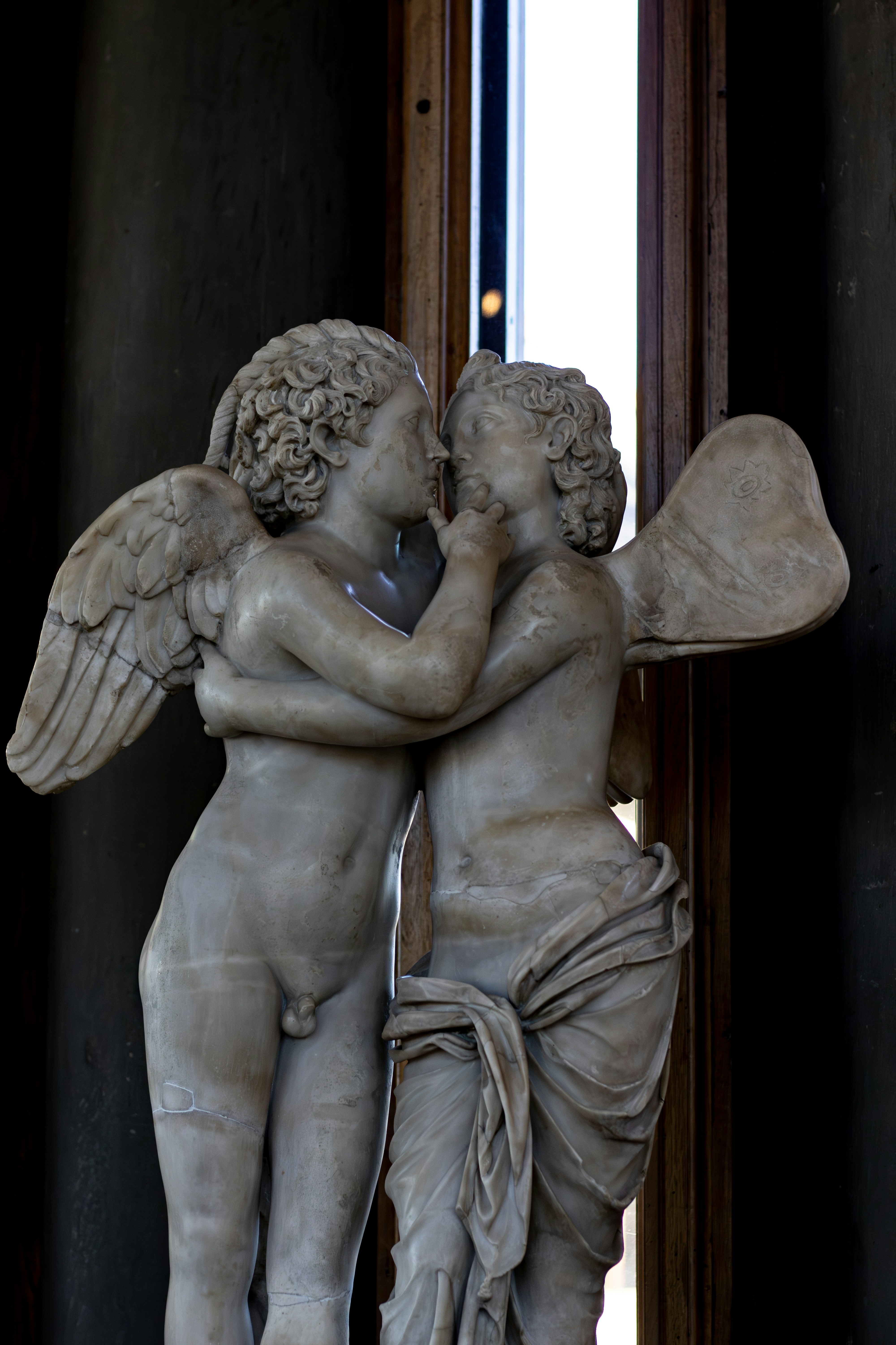 Marble Whisper: Cherubs Share a Quiet Kiss in a Backlit Niche