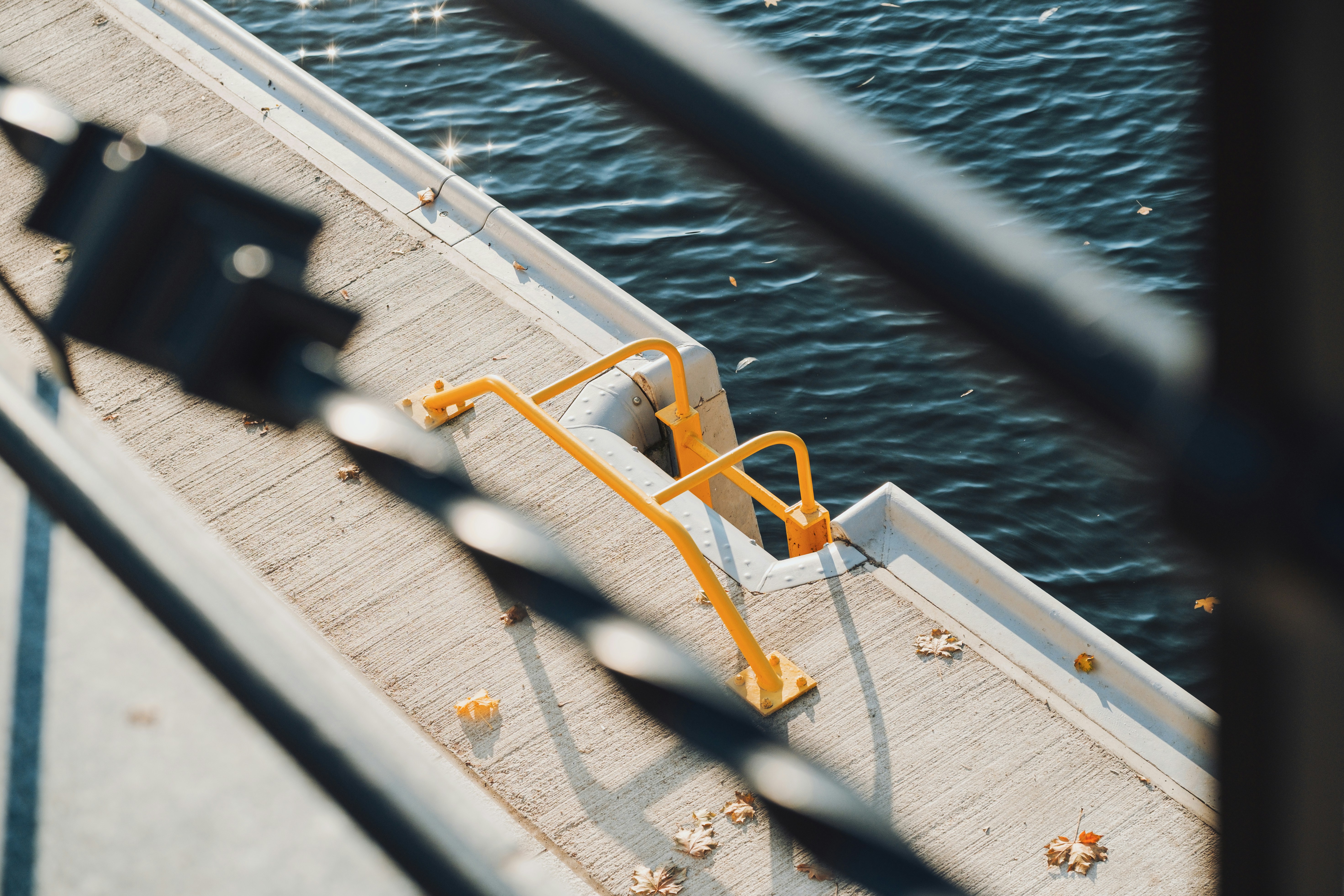 Yellow Handrail Descends Toward the Sea, Framed by Foreground Rails