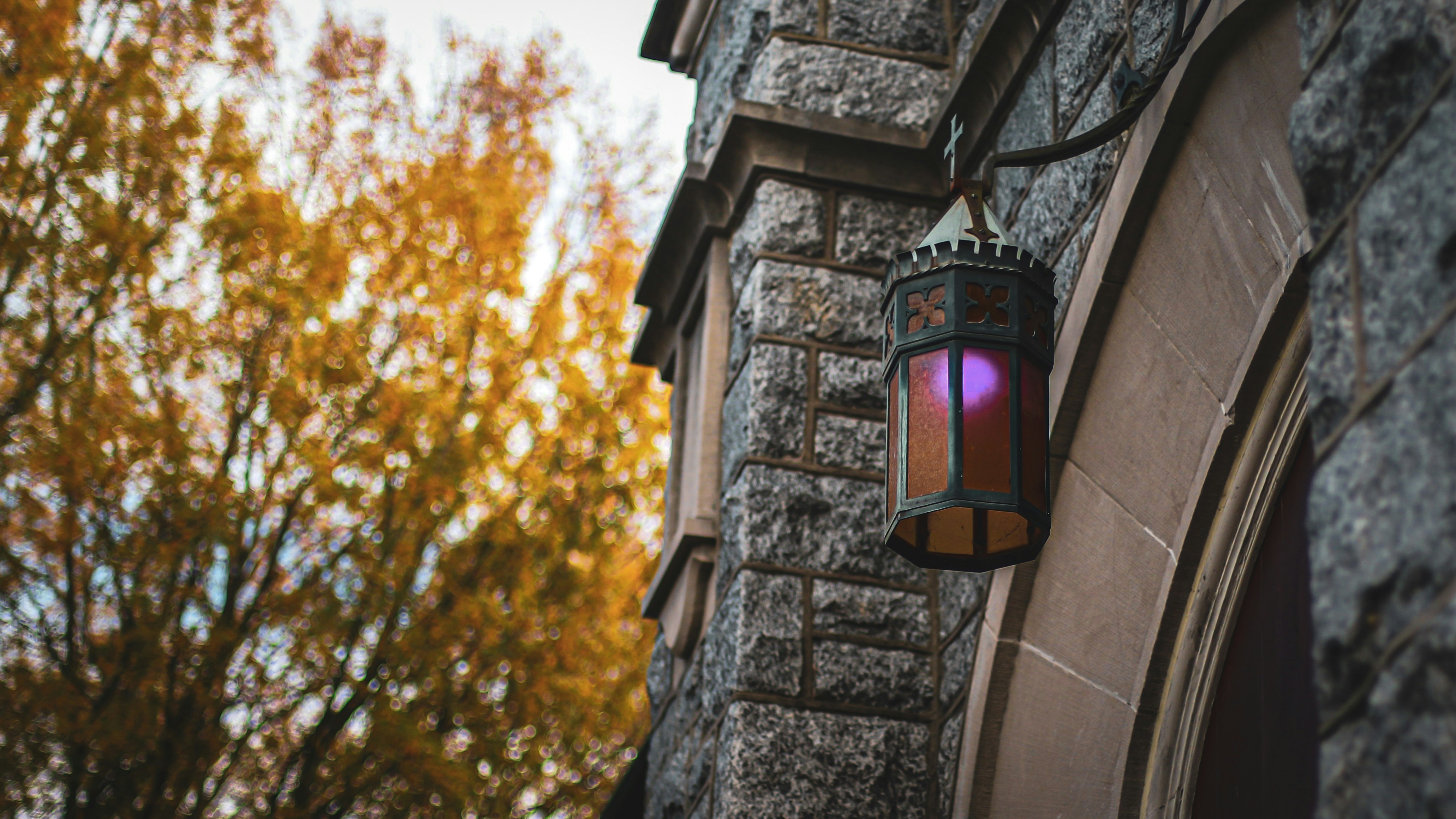 Amber Lantern on Weathered Facade: Autumn Glow by the Cobblestone Corner