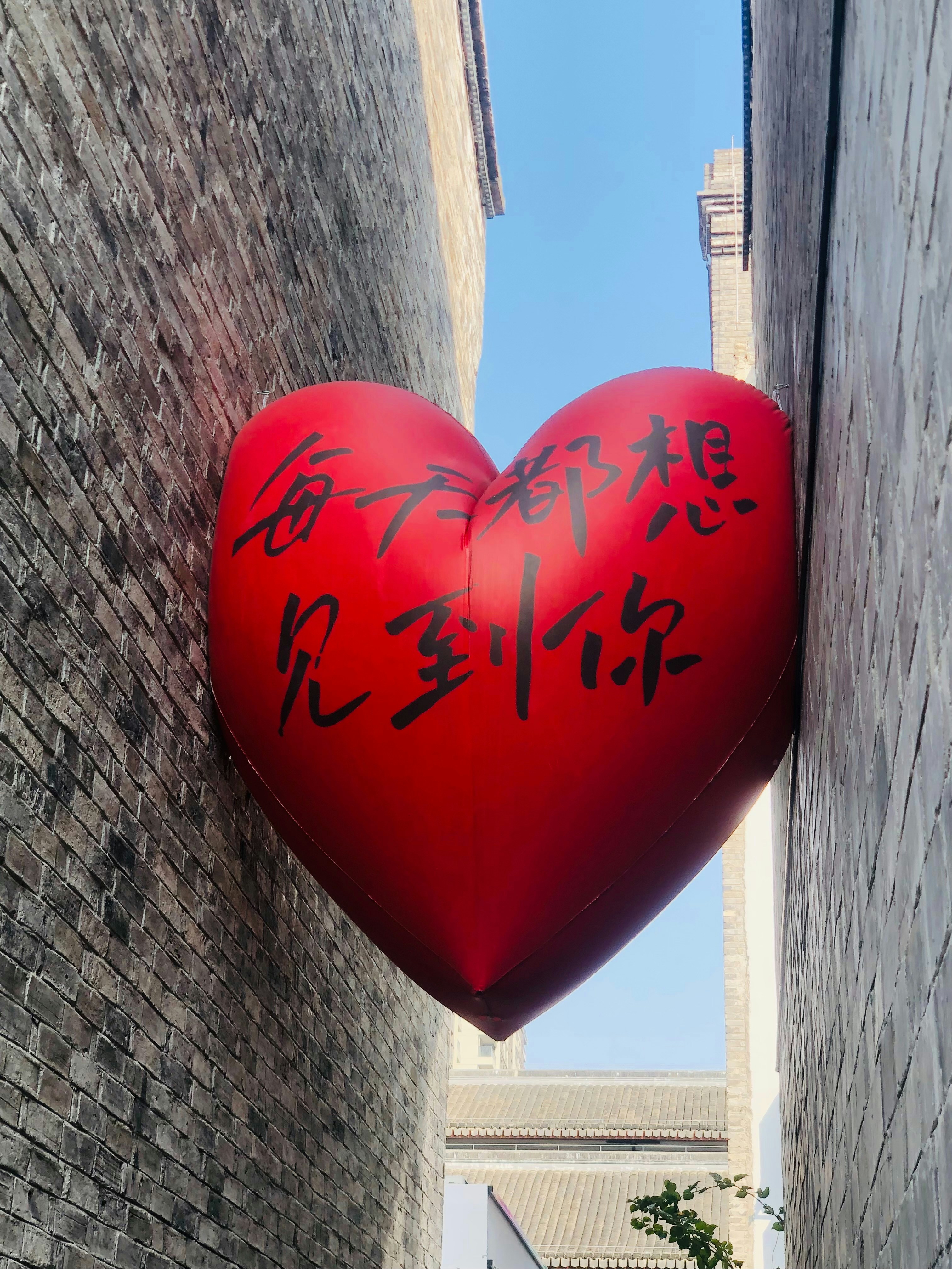 Heart Between Brick Walls: Red Symbol Framed by a Narrow Sky