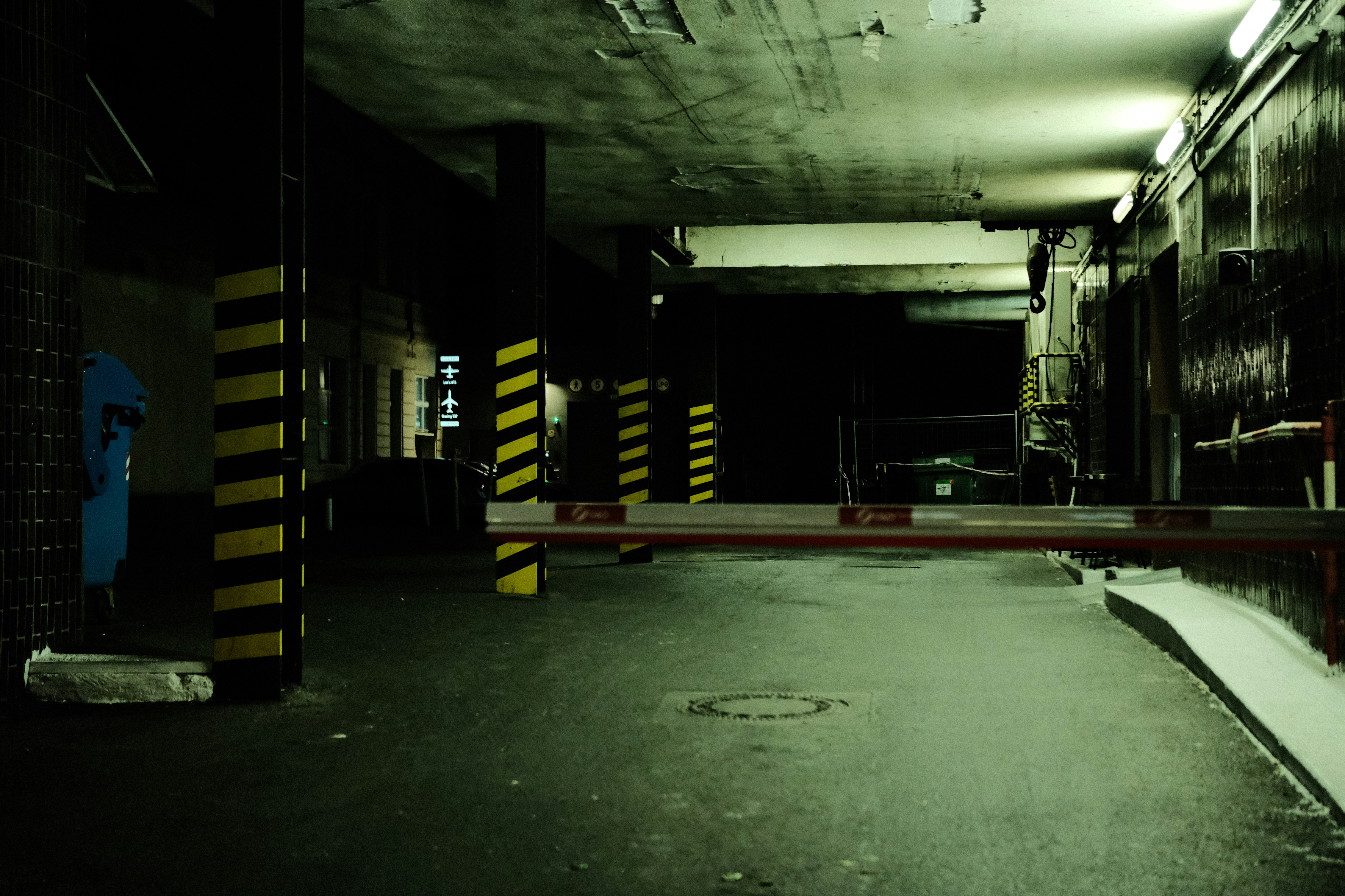 Dark garage entrance with security barrier and striped poles