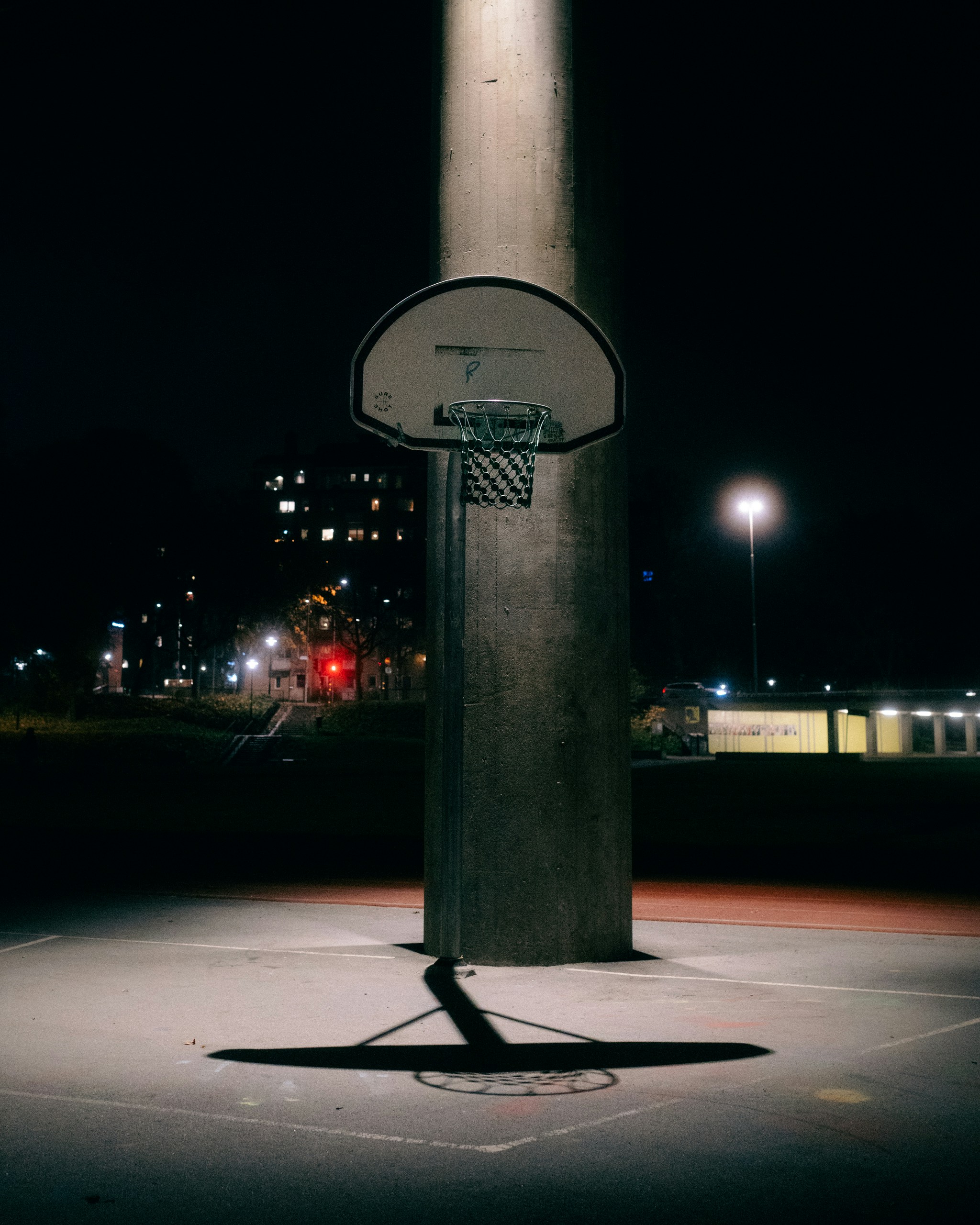 Midnight Rim: A Basketball Hoop in the Quiet City Night