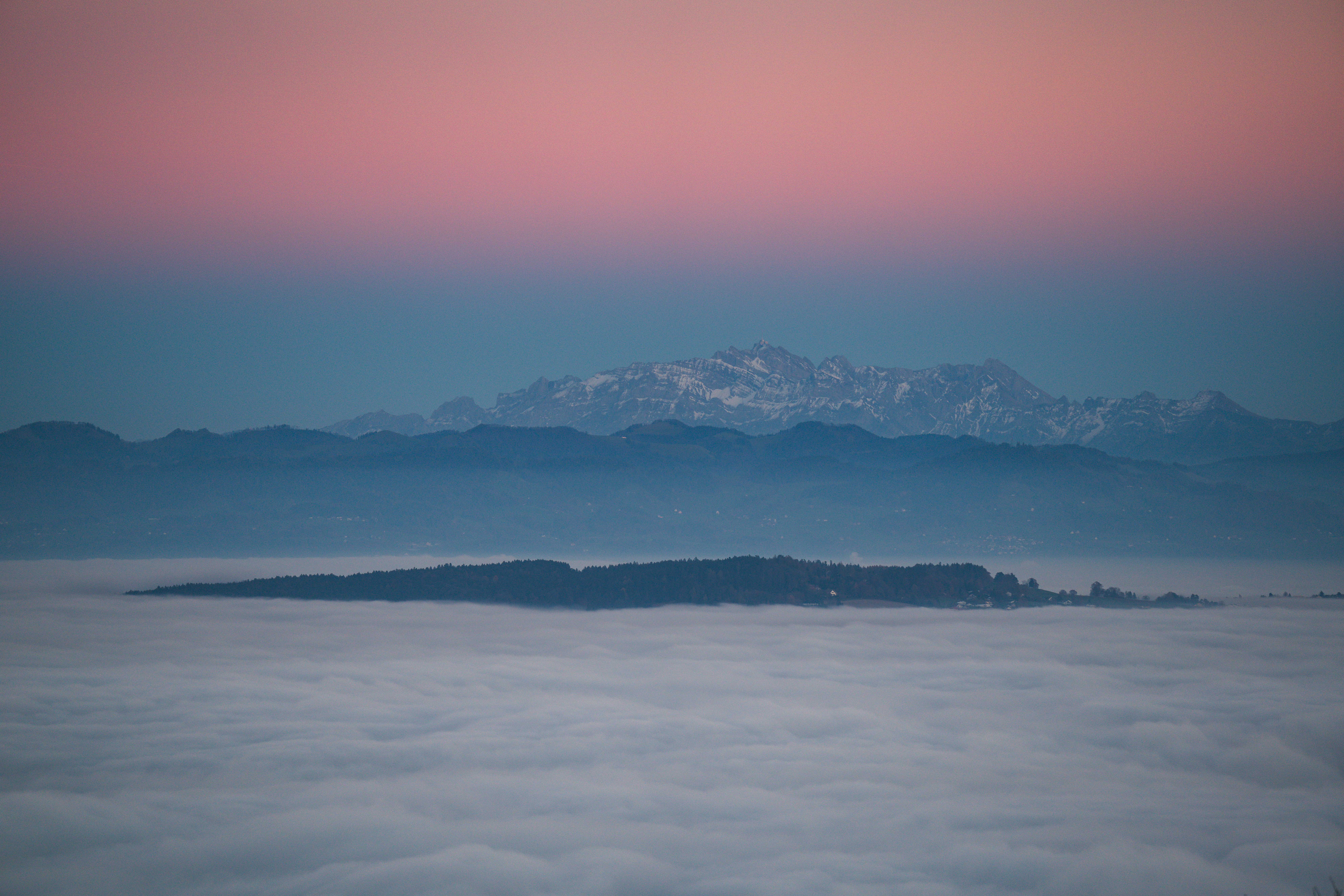 Dawn's Crest: Pink Horizon Over a Sea of Cloud and Snow