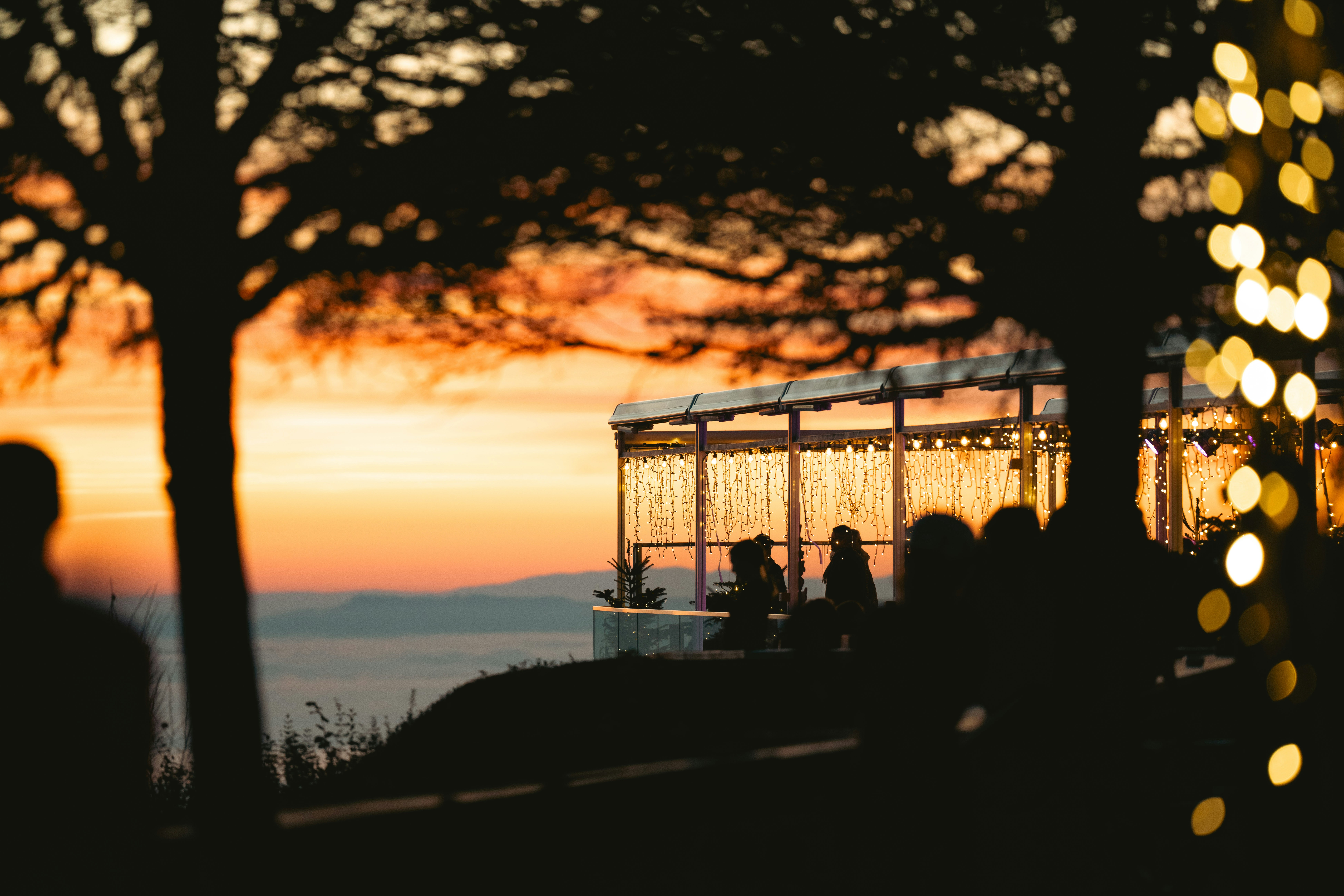 Twilight Silhouettes on a Cliffside Terrace Beneath Warm Bokeh
