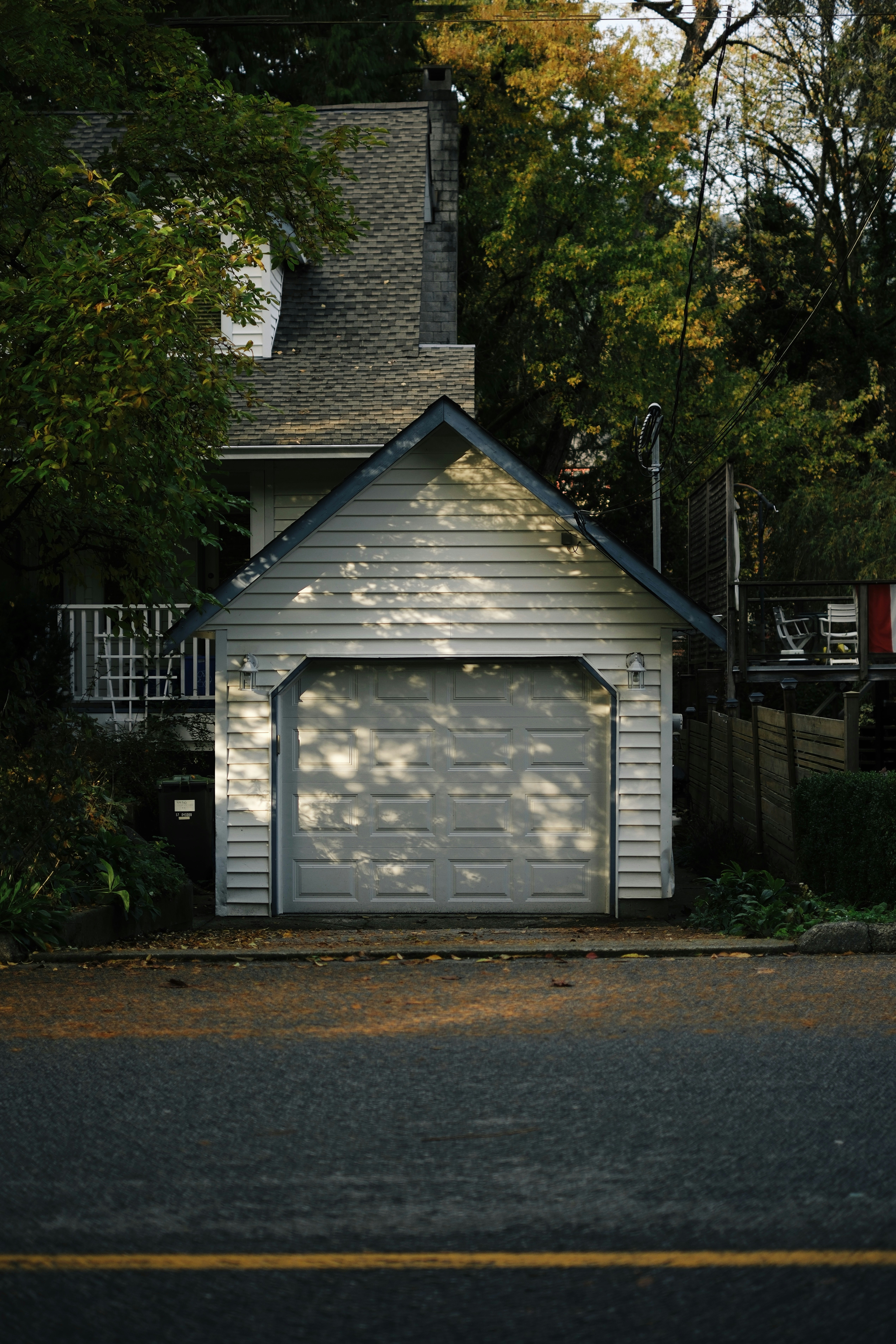 Dappled Autumn Light Across a White Garage in a Tree-Lined Street