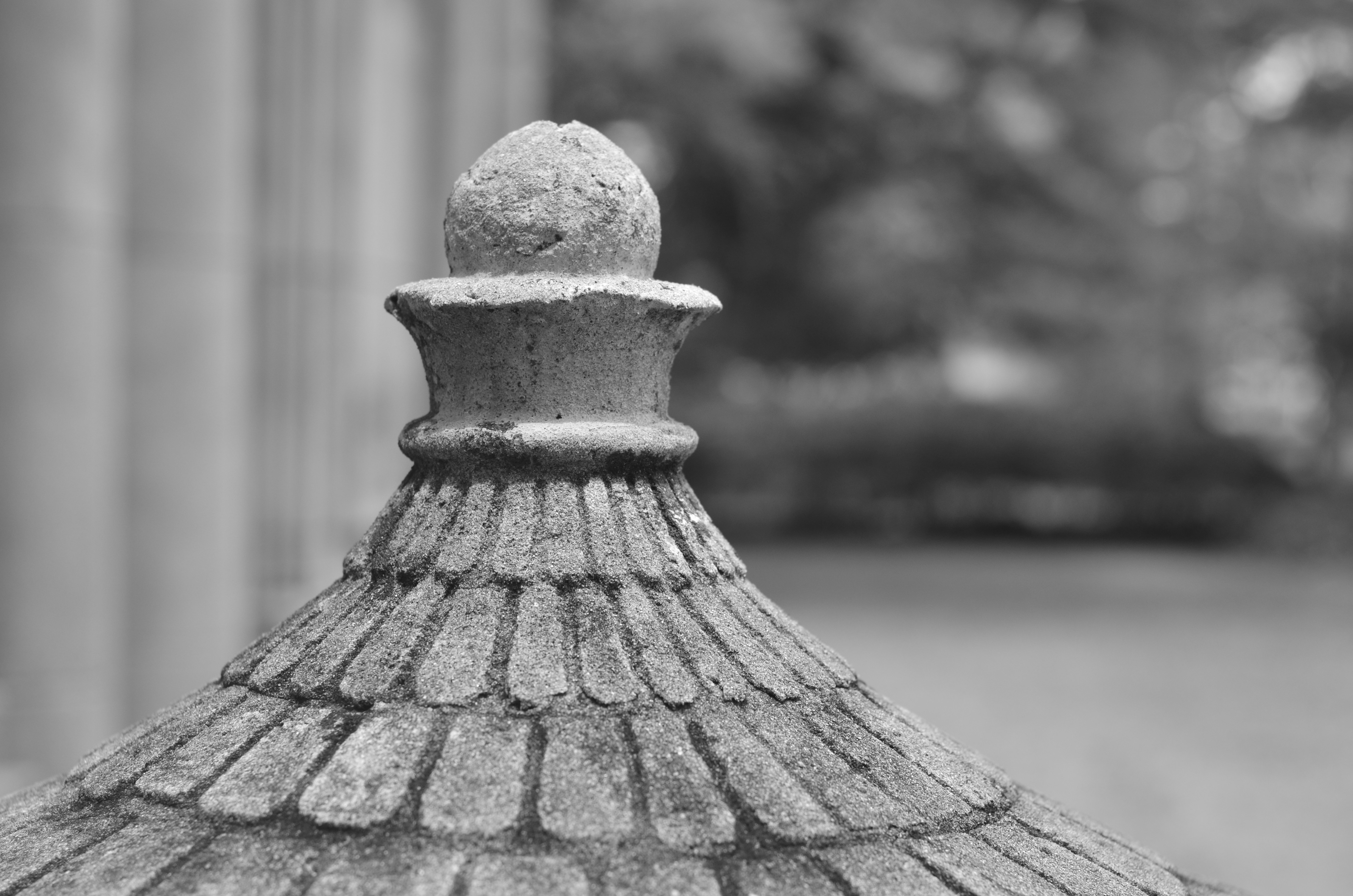 Weathered Vertex: A Quiet Close-Up of Stone Finial and Tiled Roof Texture