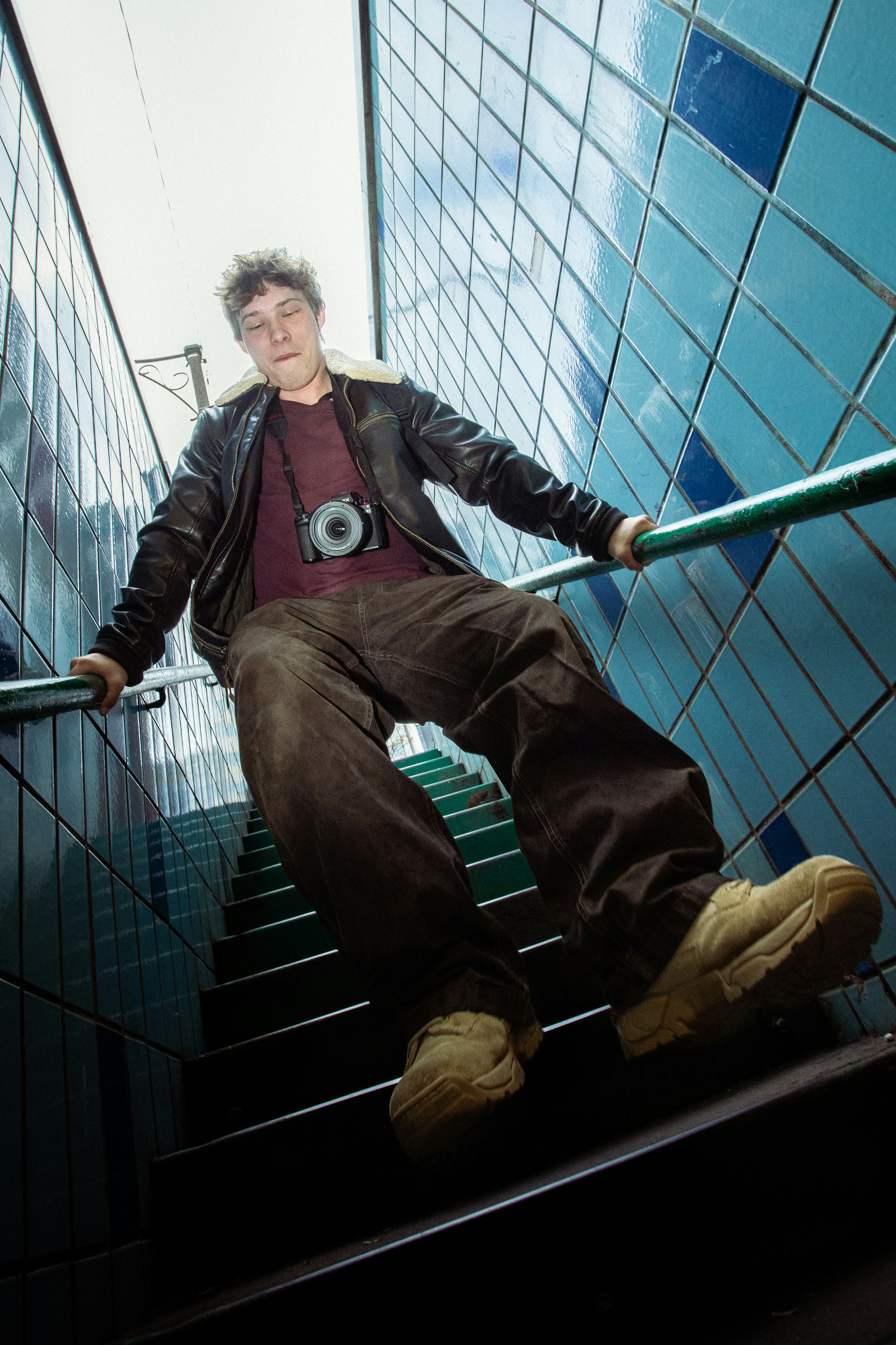 Blue-Tiled Descent: A Low-Angle Portrait of a Man with a Camera
