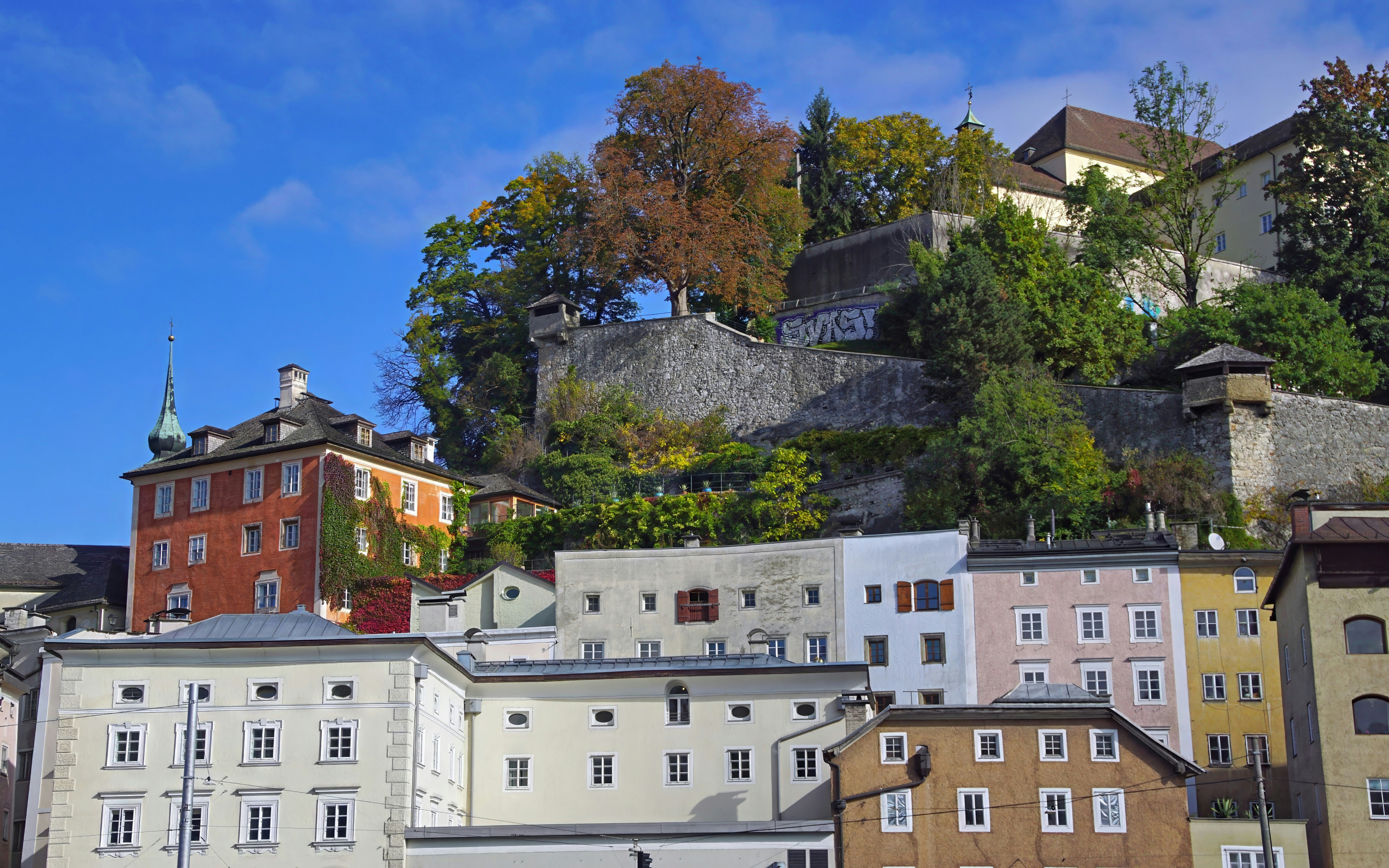 Hillside old houses and an even older wall with watchtowers in Salzburg, Austria.