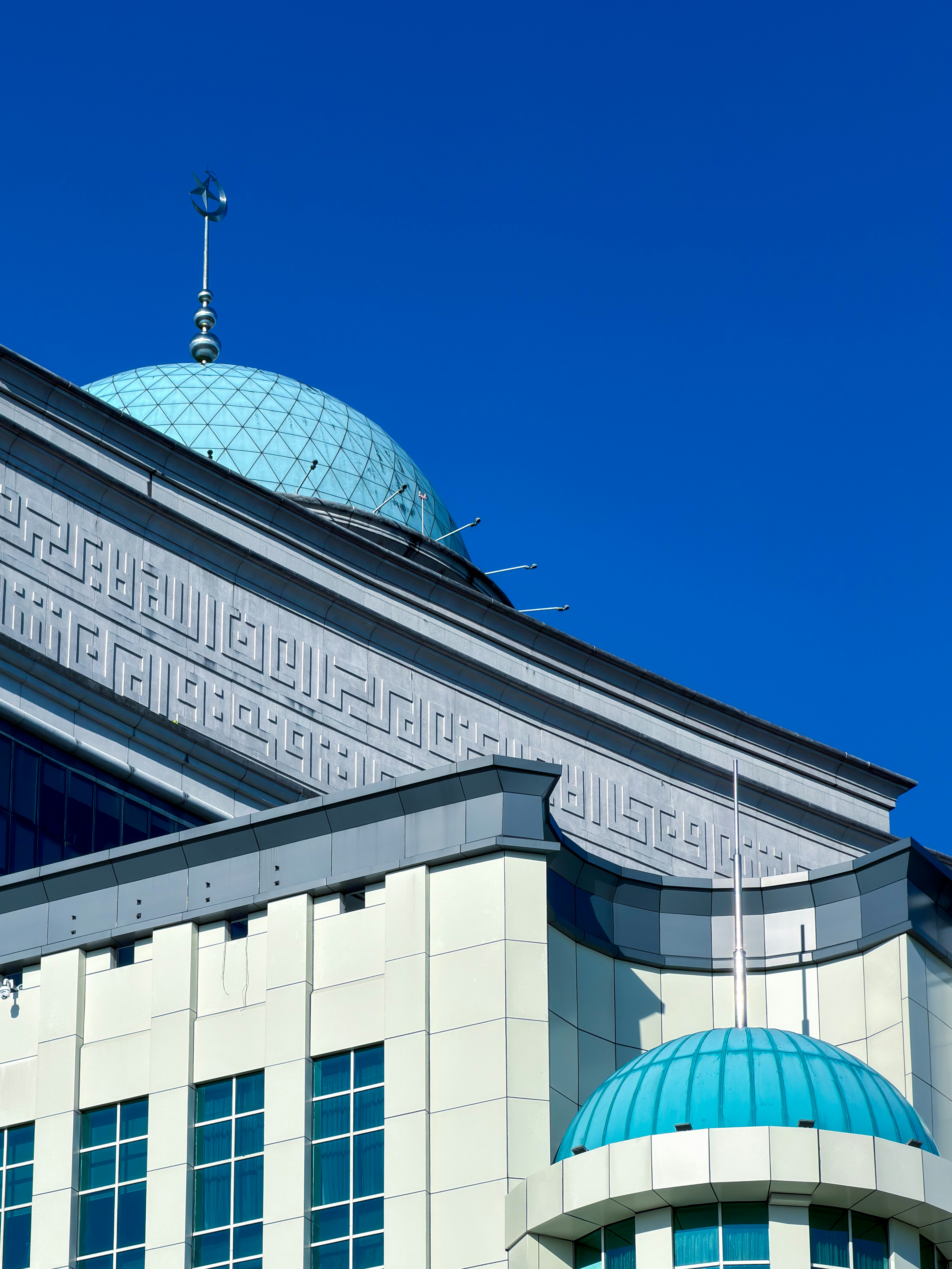 Turquoise Domes Crown a Linear Modernist Facade Beneath Cerulean Skies