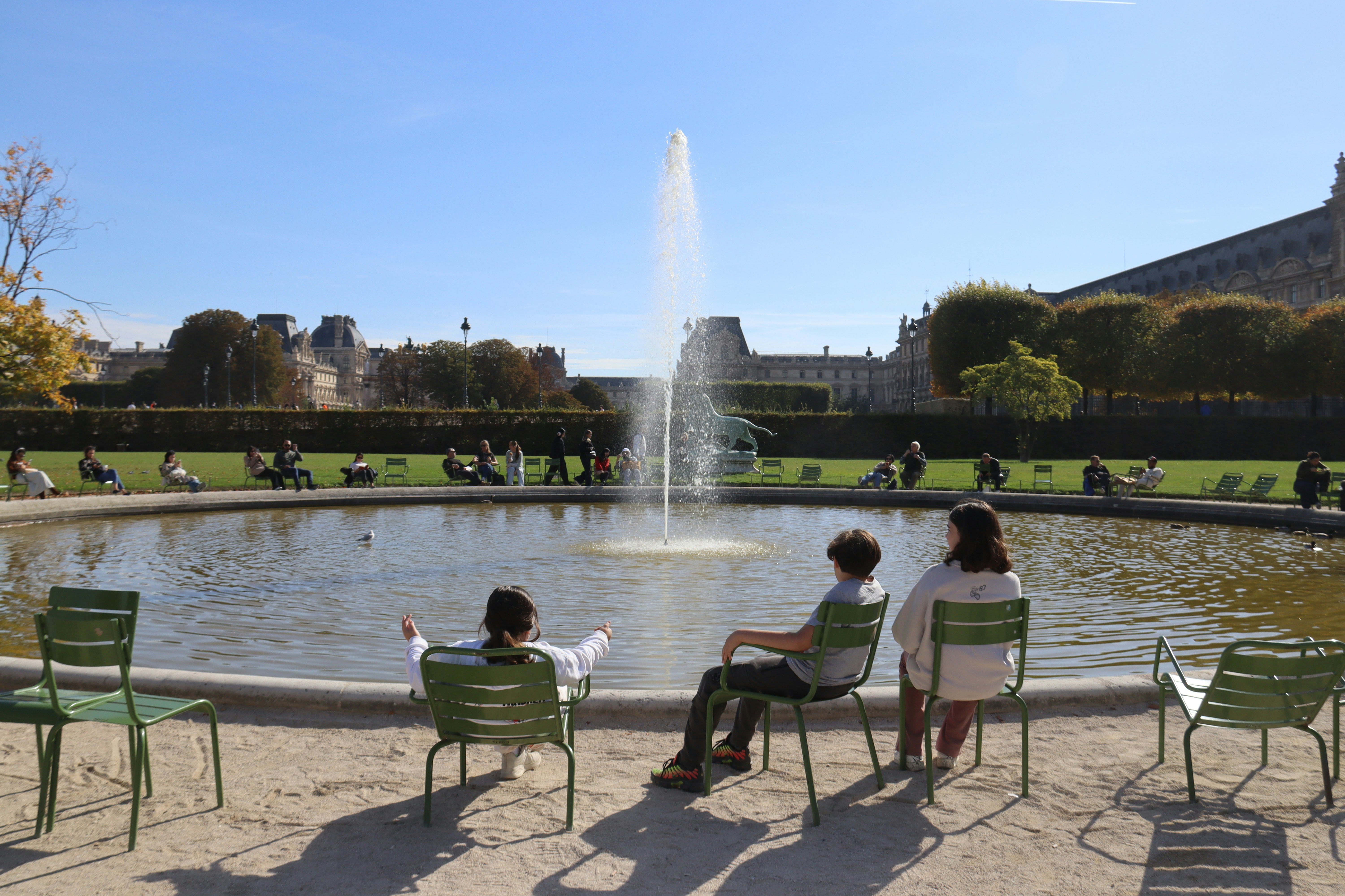 People relaxing by a fountain in a sunny park.