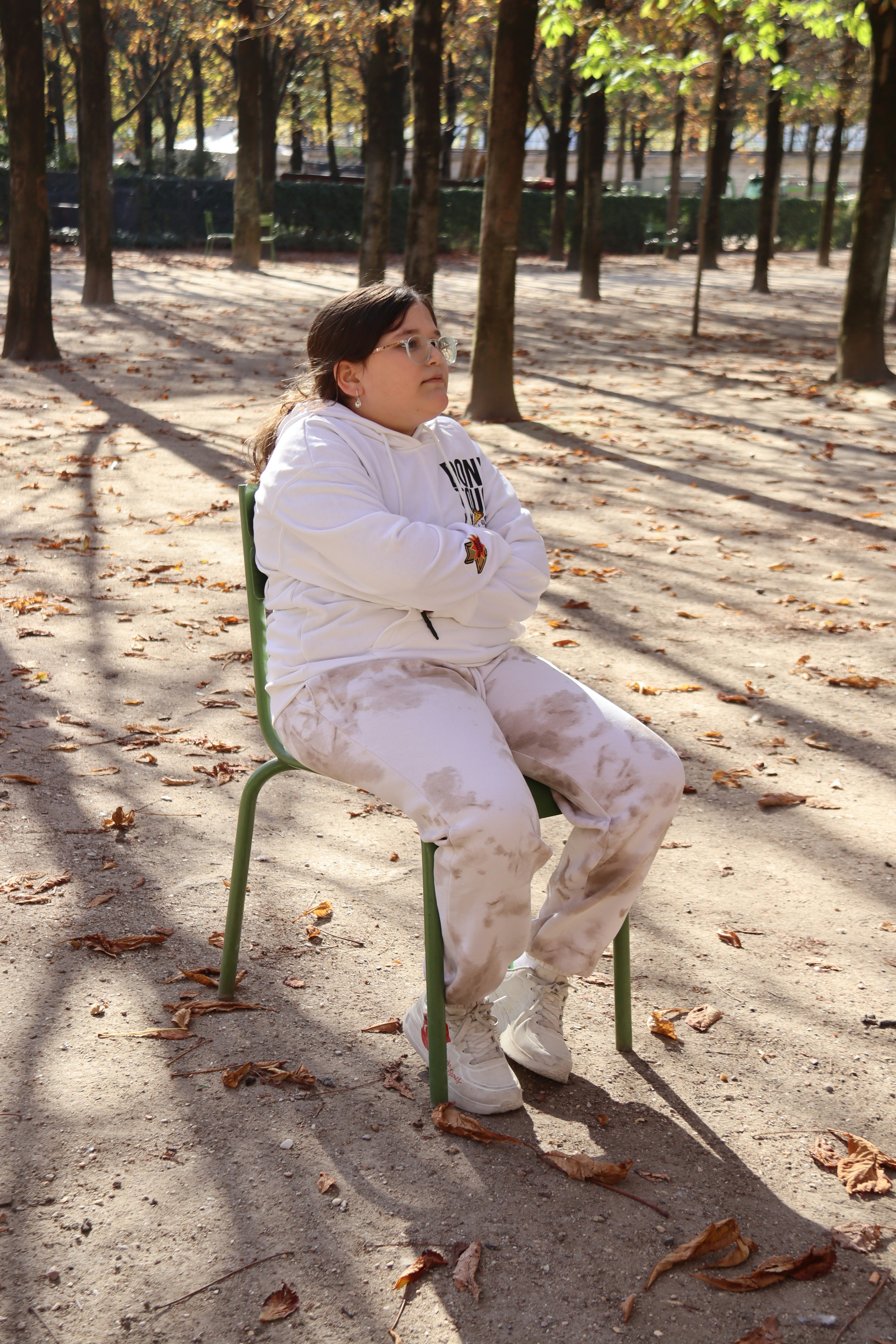 Dappled Light Portrait: Seated Figure in a Leaf-Strewn Park