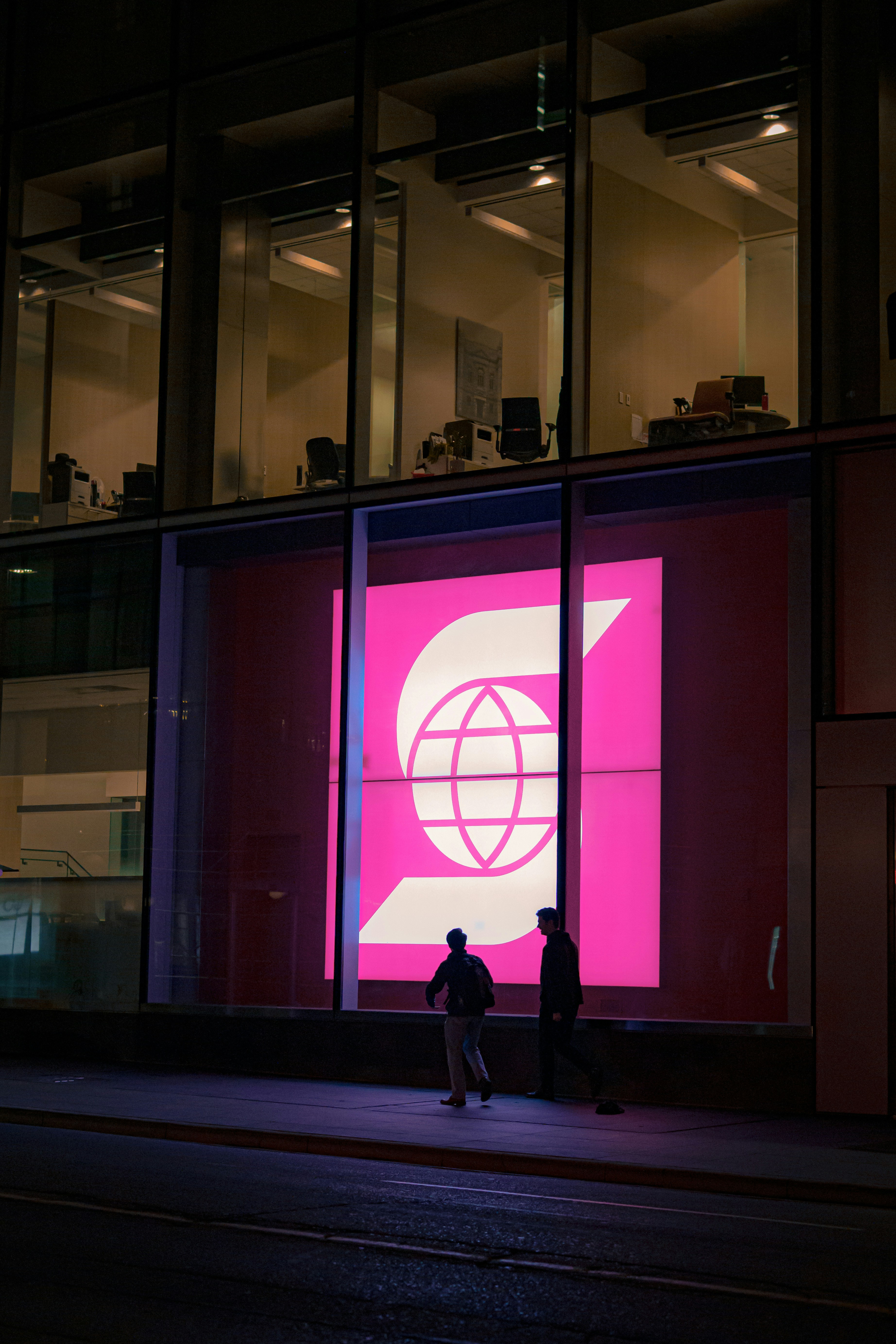 Neon Globe Window: Night Walks by a Magenta Display