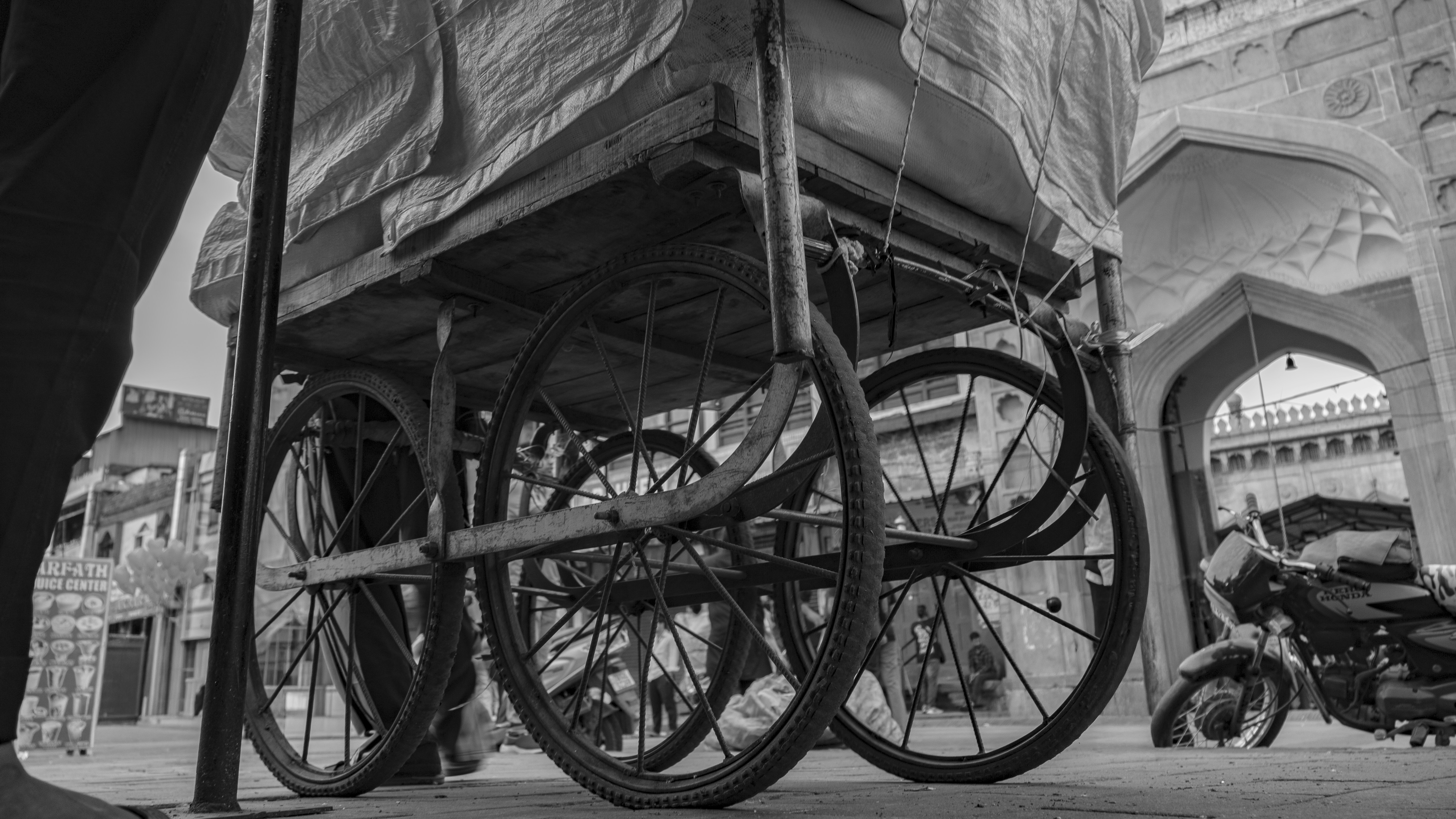 Wheelwork Under Arches: A Monochrome Street Cart Study