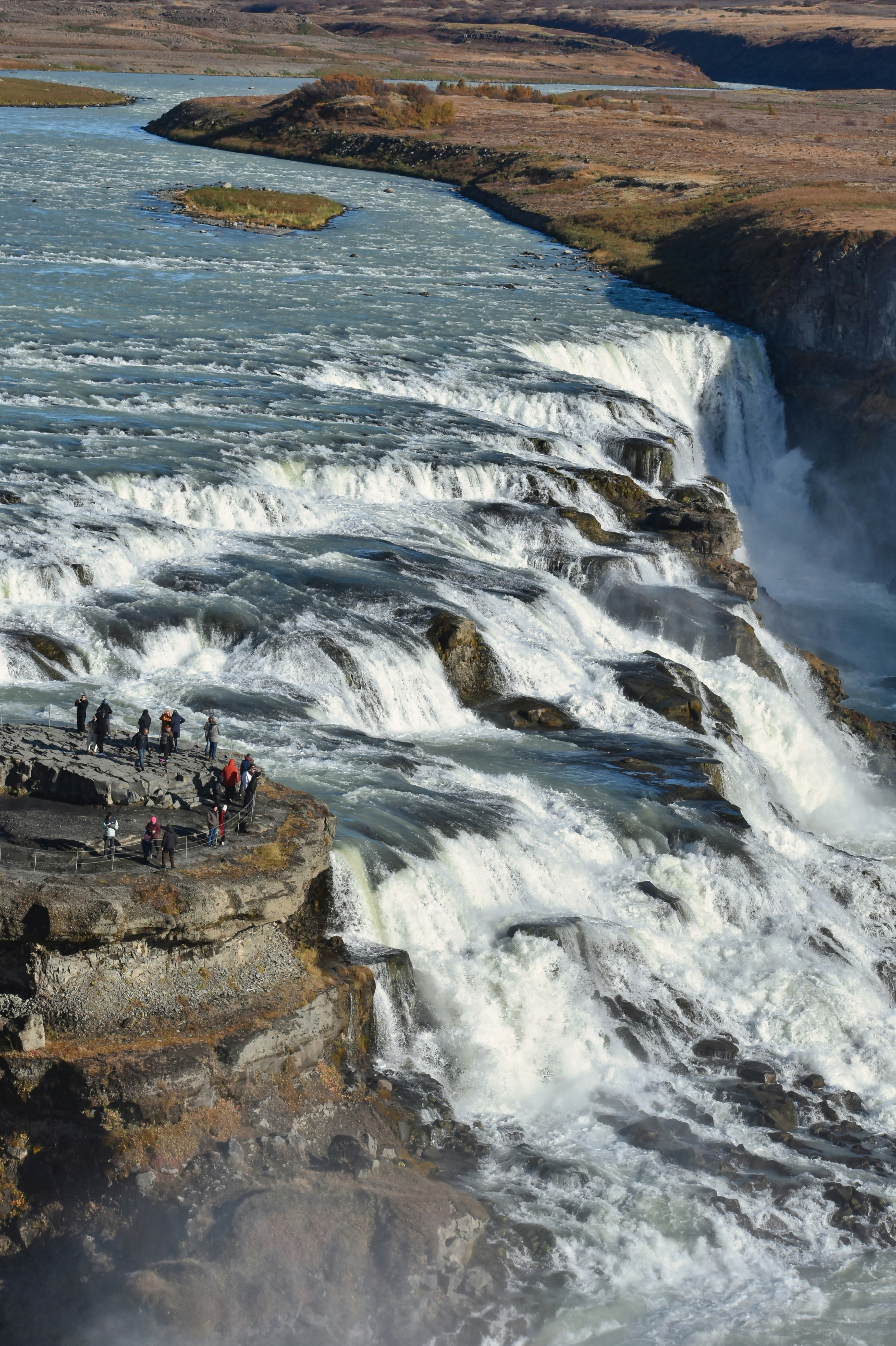 Overlook on the Edge: Tourists Watching a Roaring Cascade from a Rocky Promontory