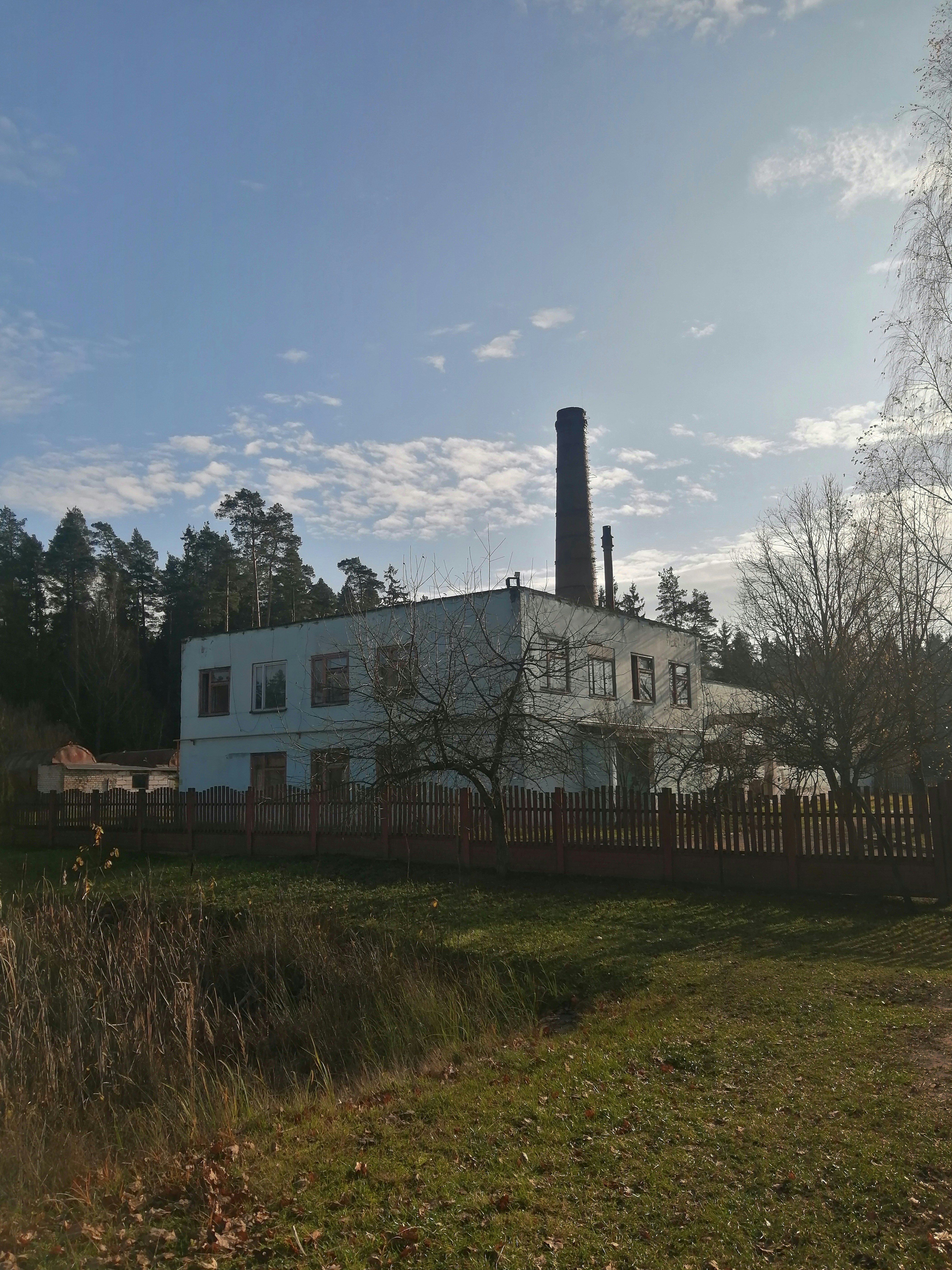 Blue Facade and a Lone Chimney: Quiet Industrial Scene Under Open Sky