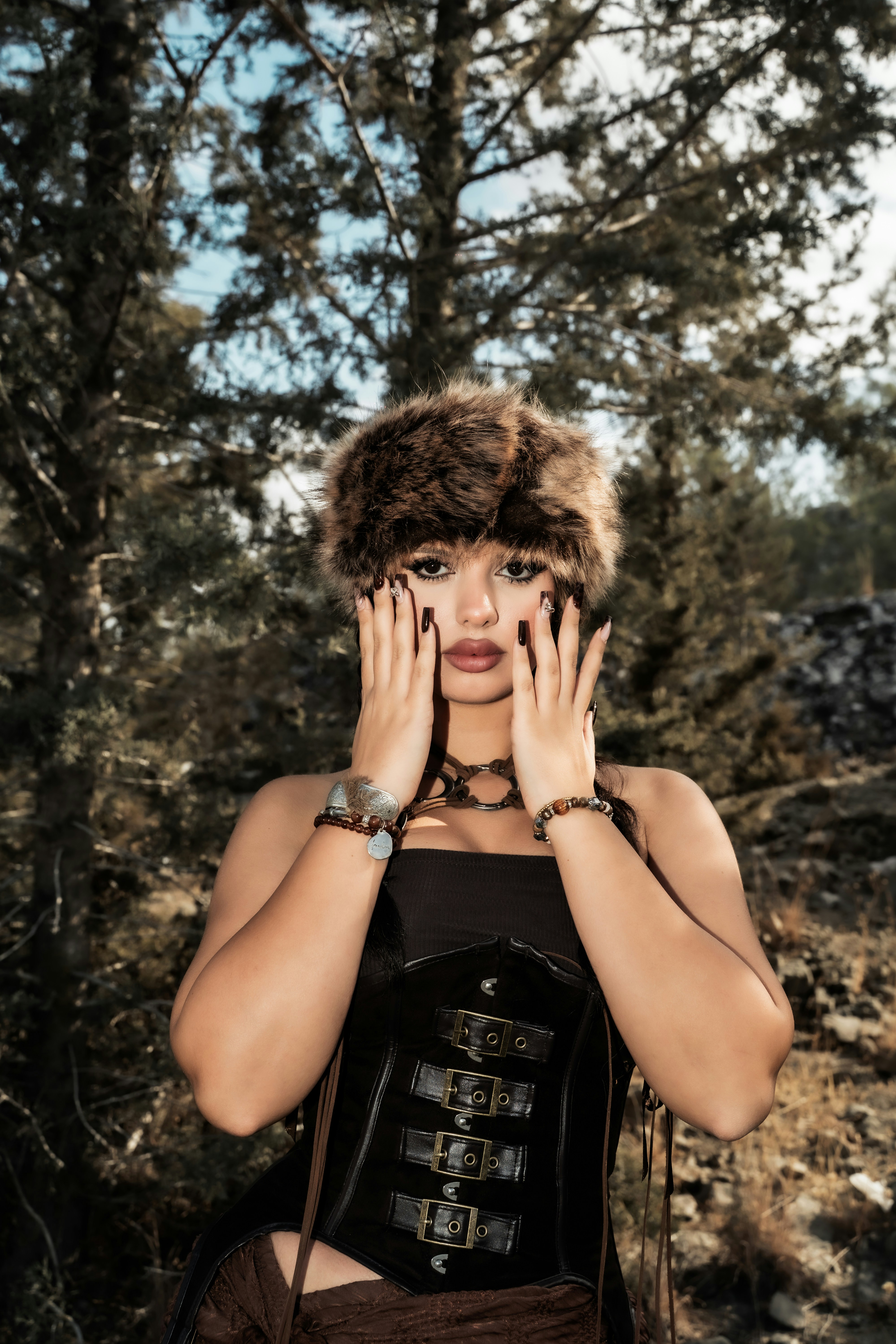 Fierce portrait of a woman in rustic attire with fur hat and natural jewelry.