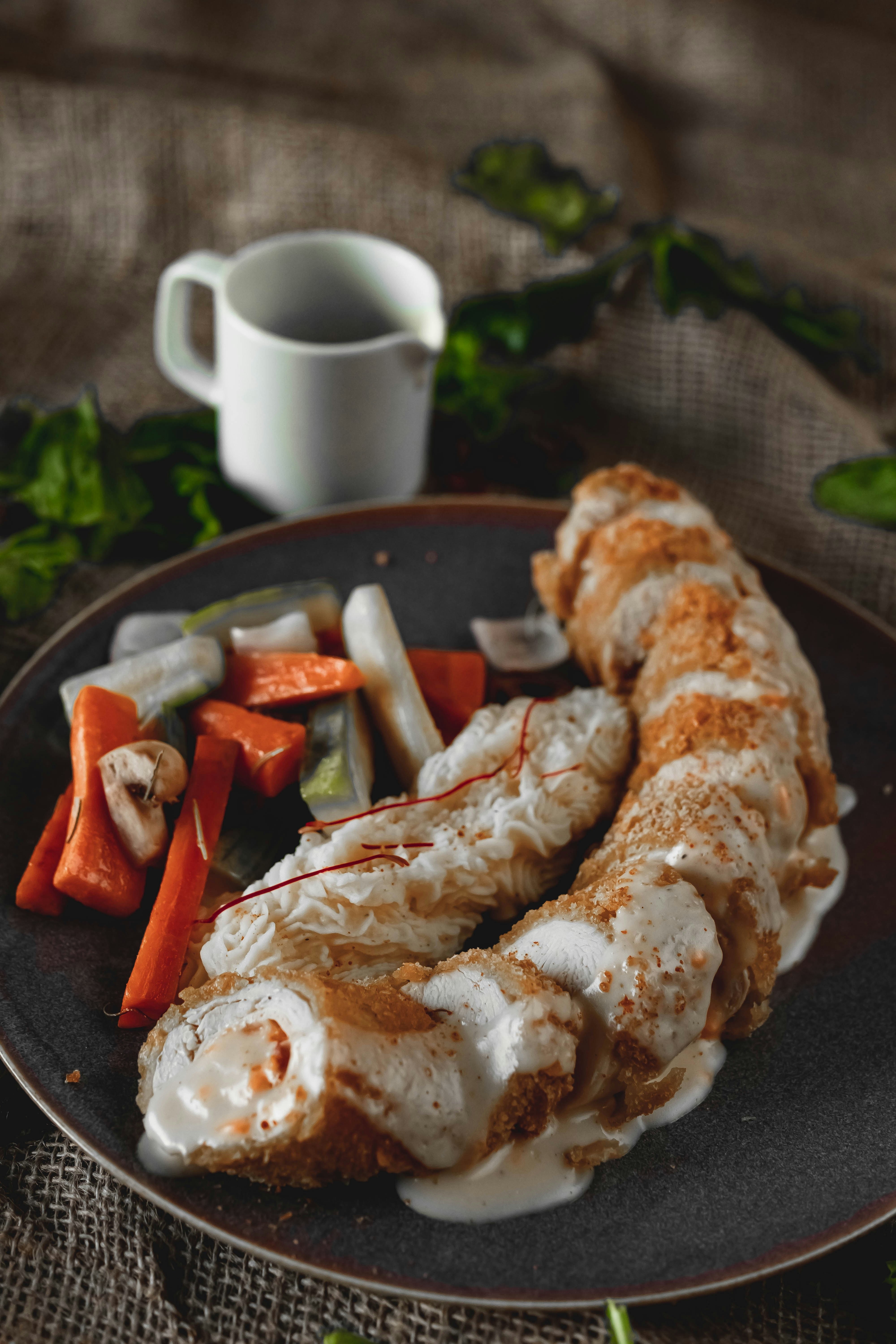Cream-Draped Chicken Ribbons Framed by Carrot Mosaic on a Rustic Plate