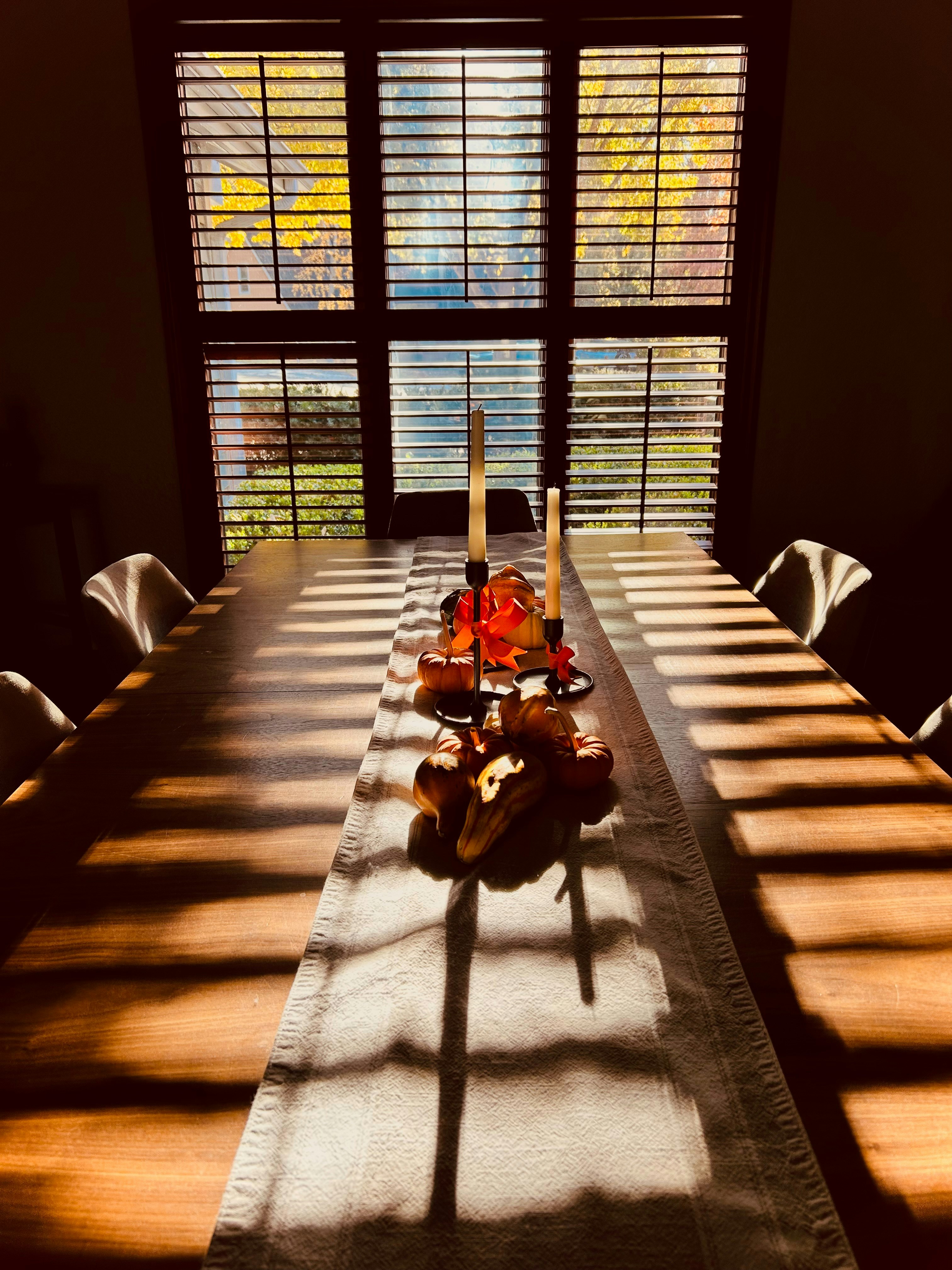 Dining table with autumn foliage visible through window.
