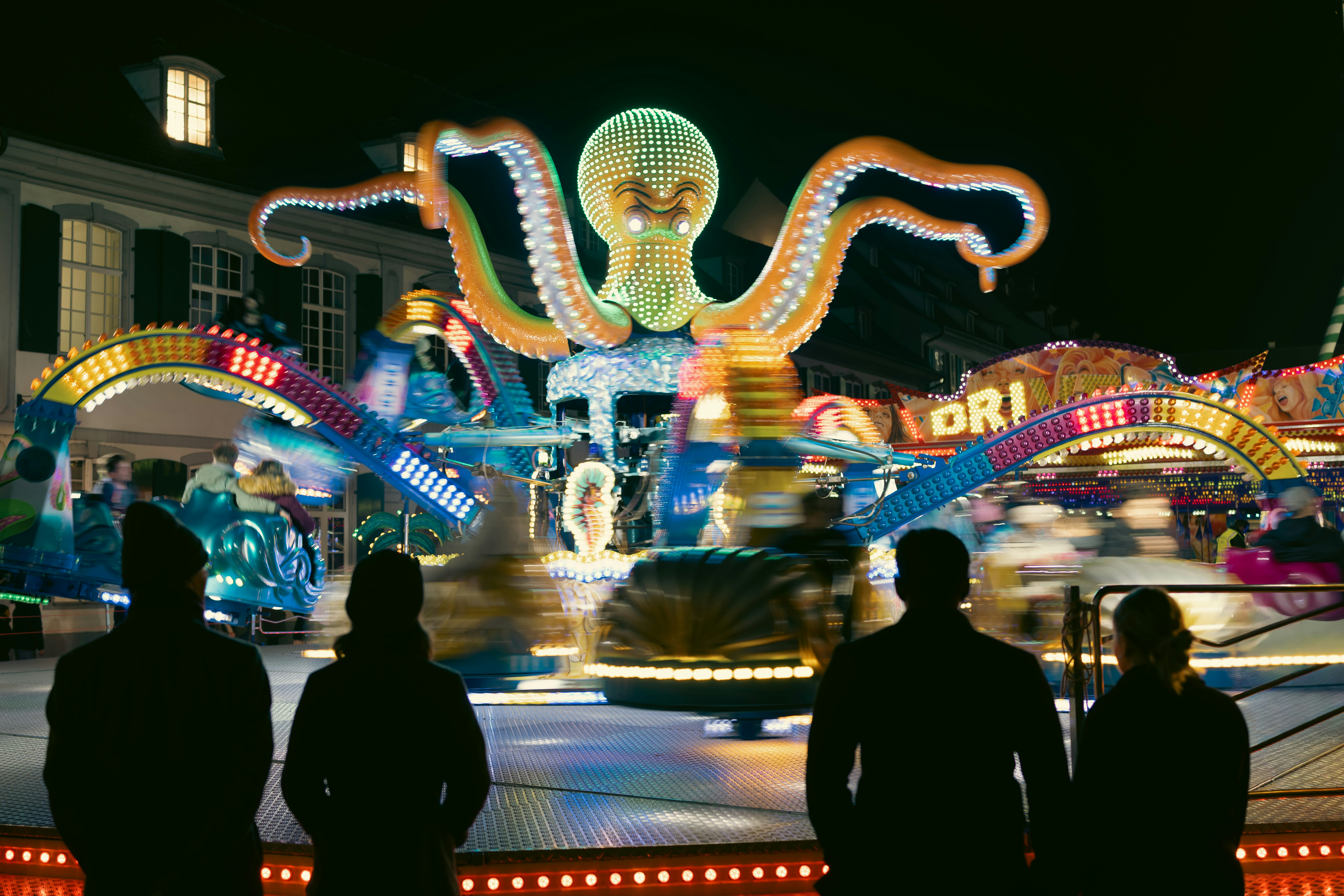 People watch a spinning octopus amusement park ride at night photo ...