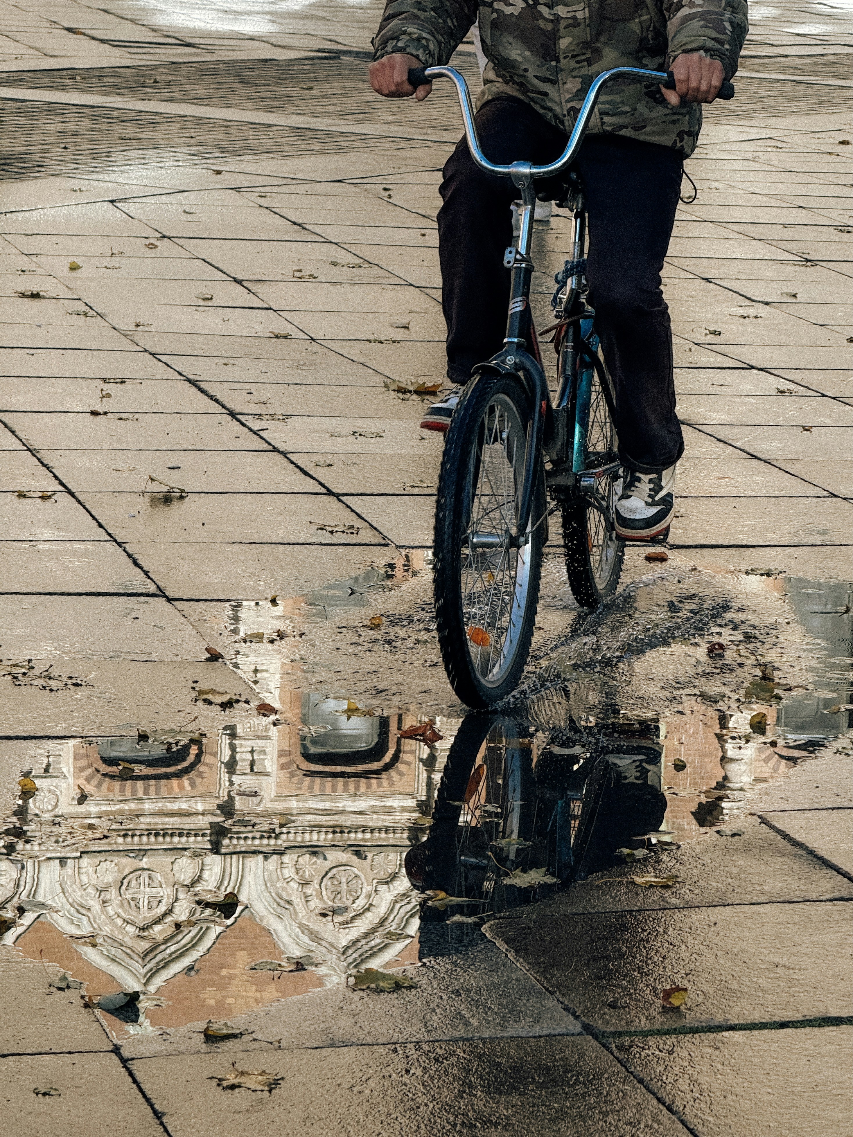Mirrored Ride: Blue Bicycle and Cathedral Reflections on Wet Pavers