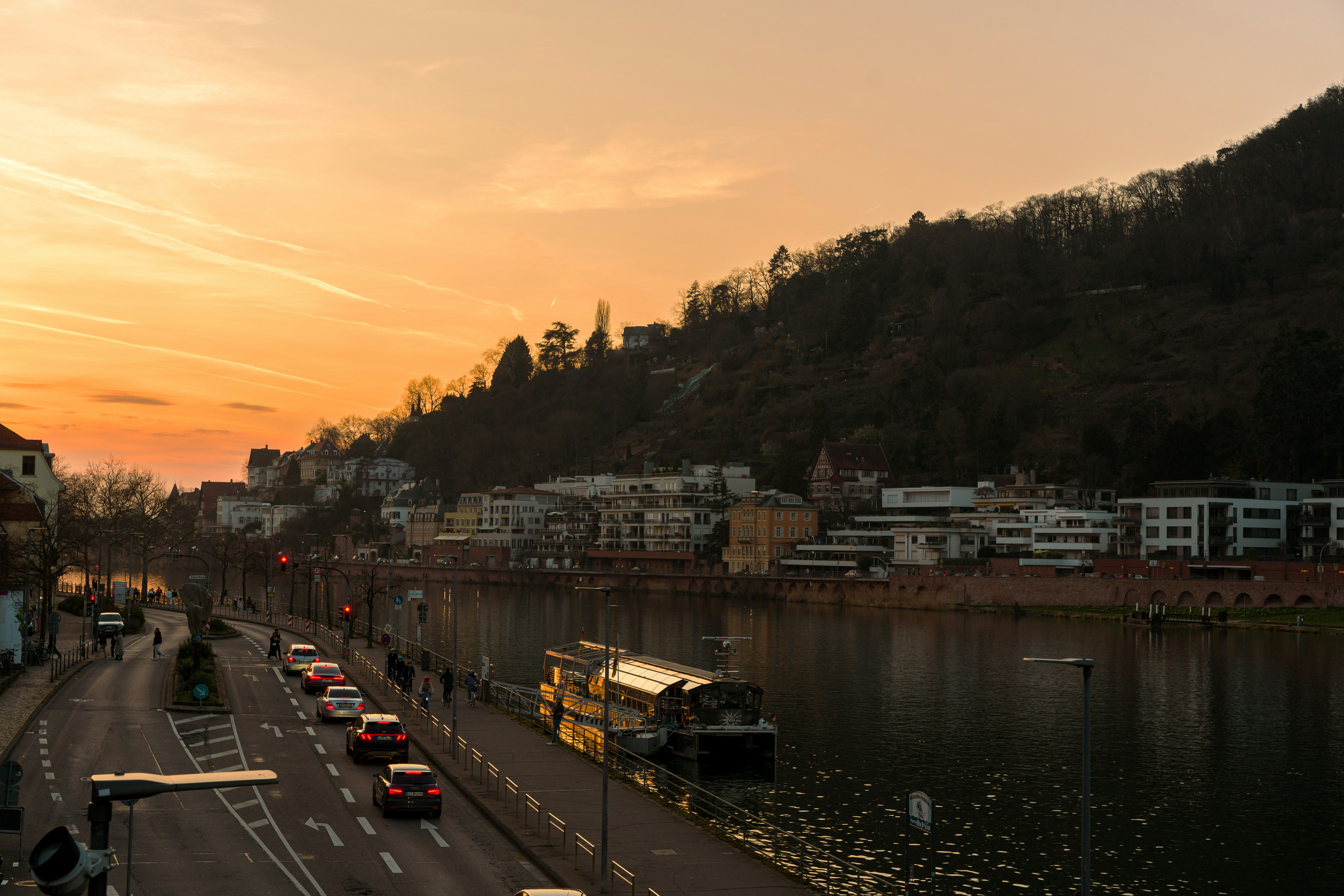 Golden Hour on the Riverfront: Boat Glide and Hillside Glow