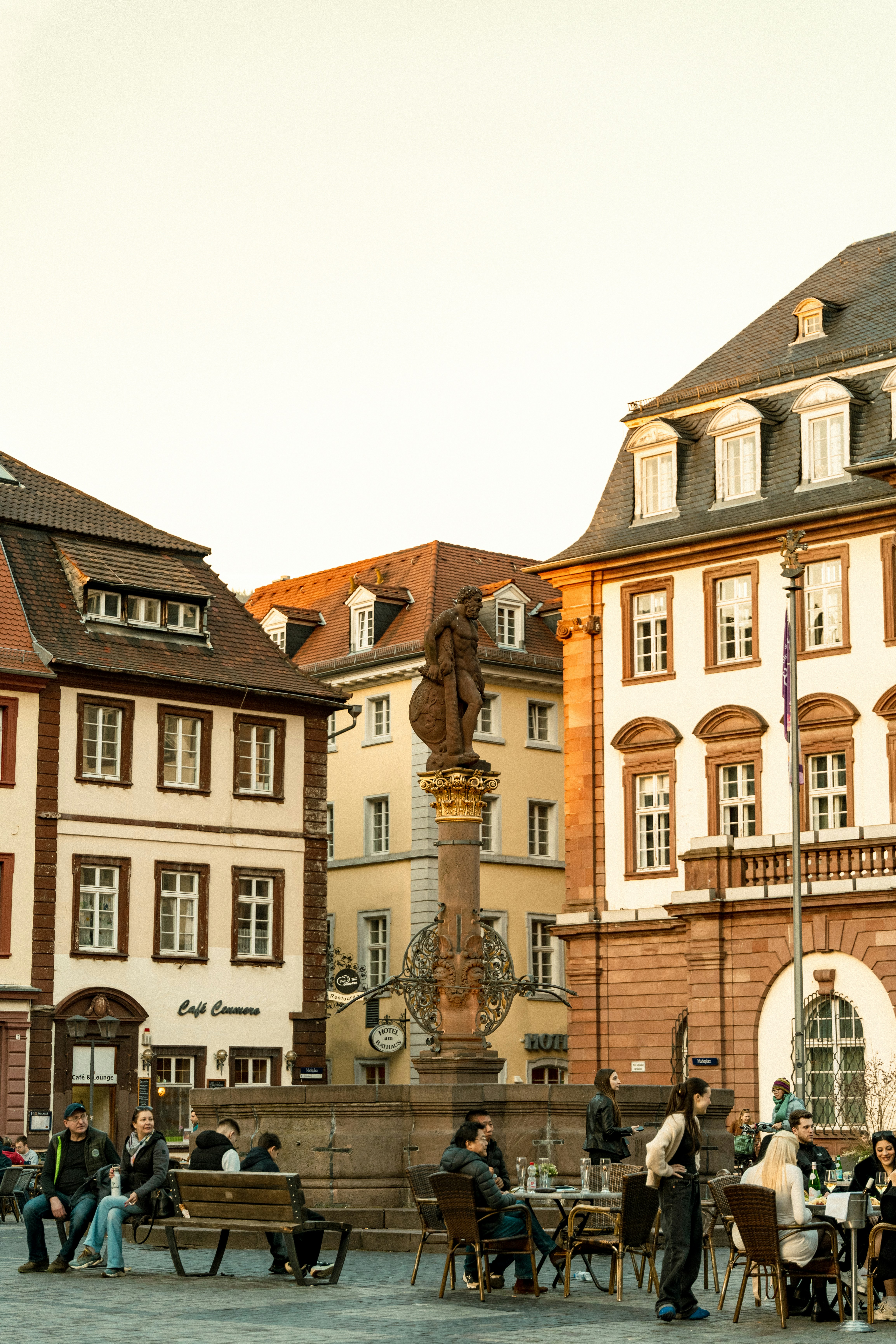 People sitting at tables in a european town square. photo – Free ...