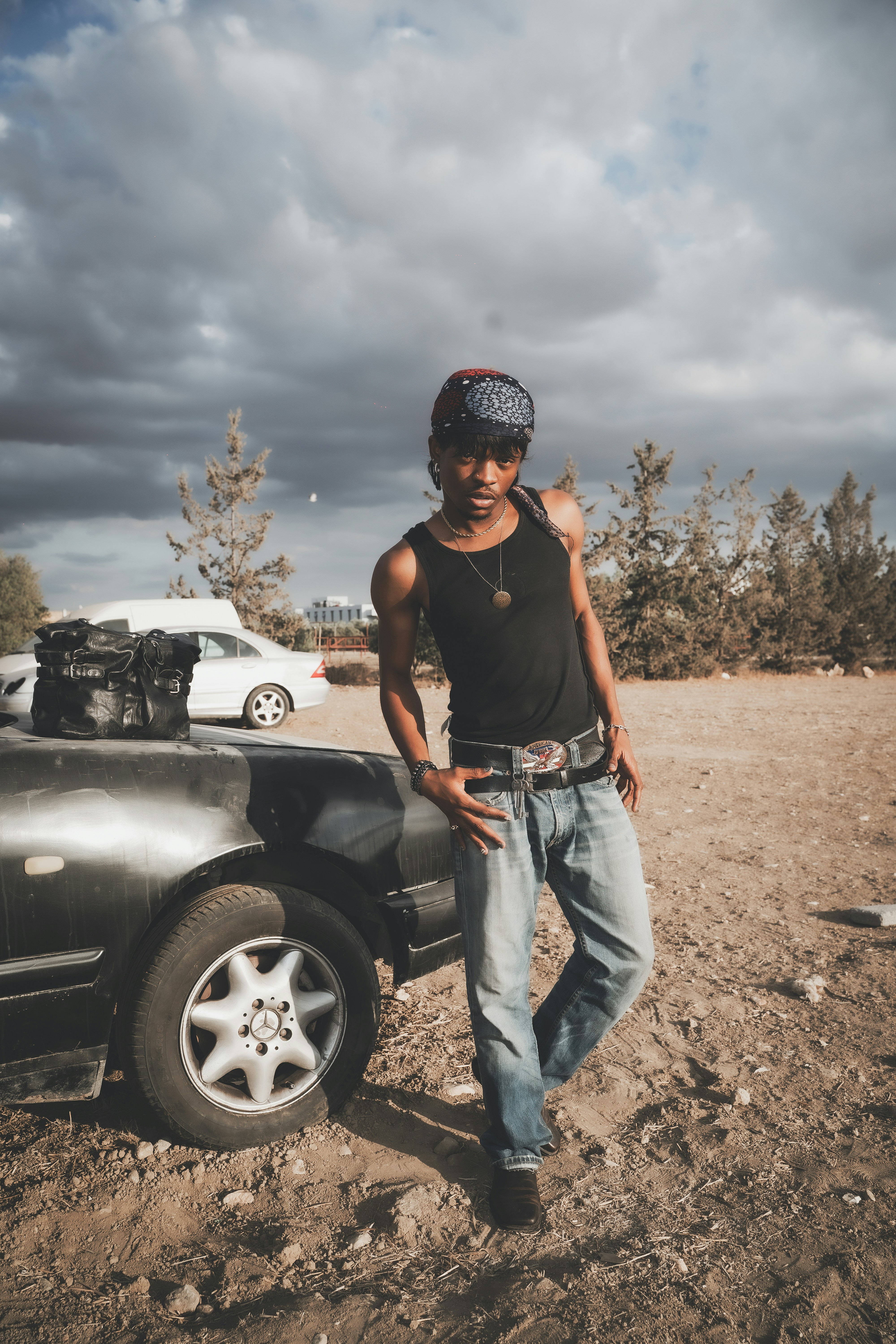 man in a junkyard behind a car walking forward