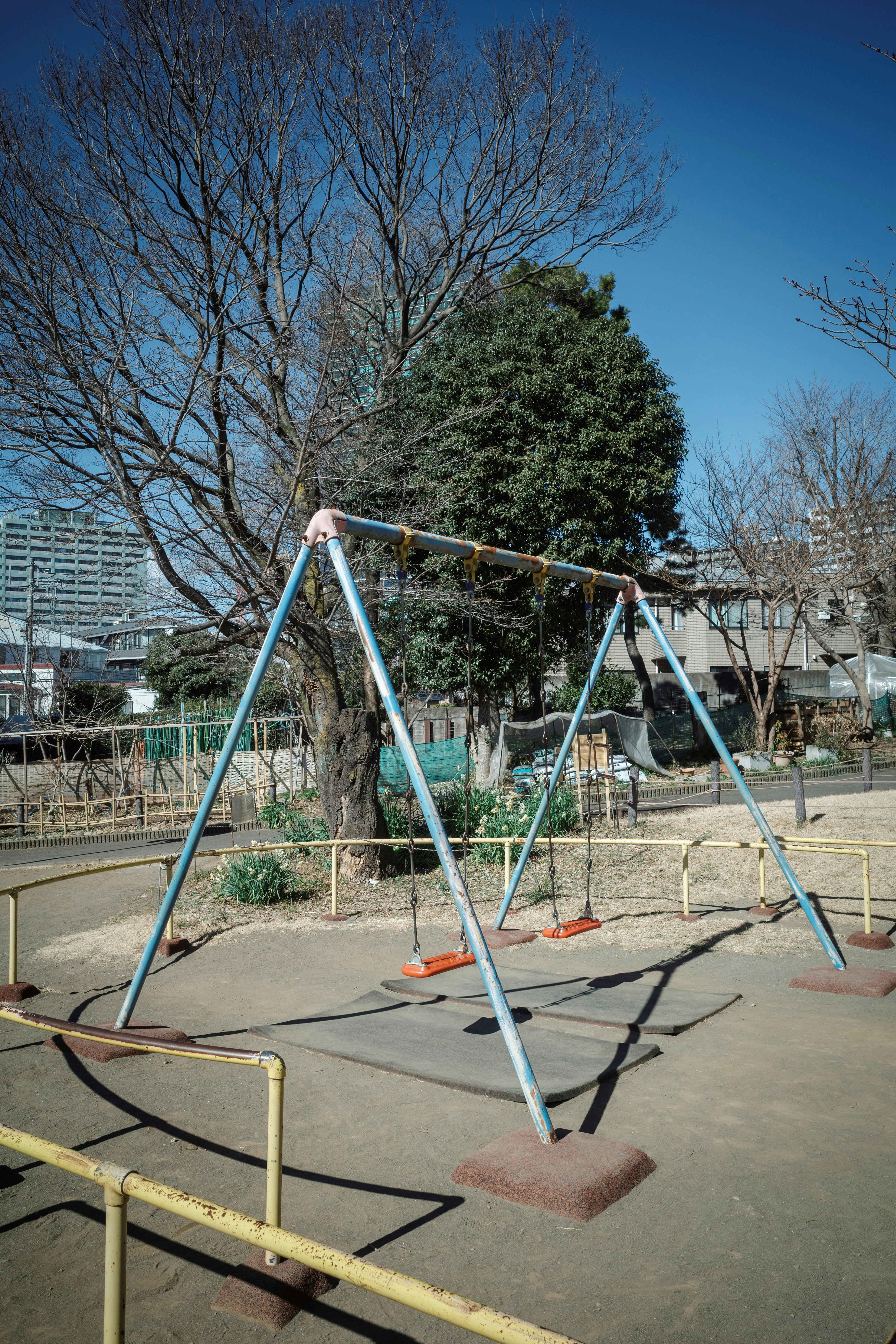 Blue Swing Set Under a Clear Winter Sky in a Quiet Urban Park