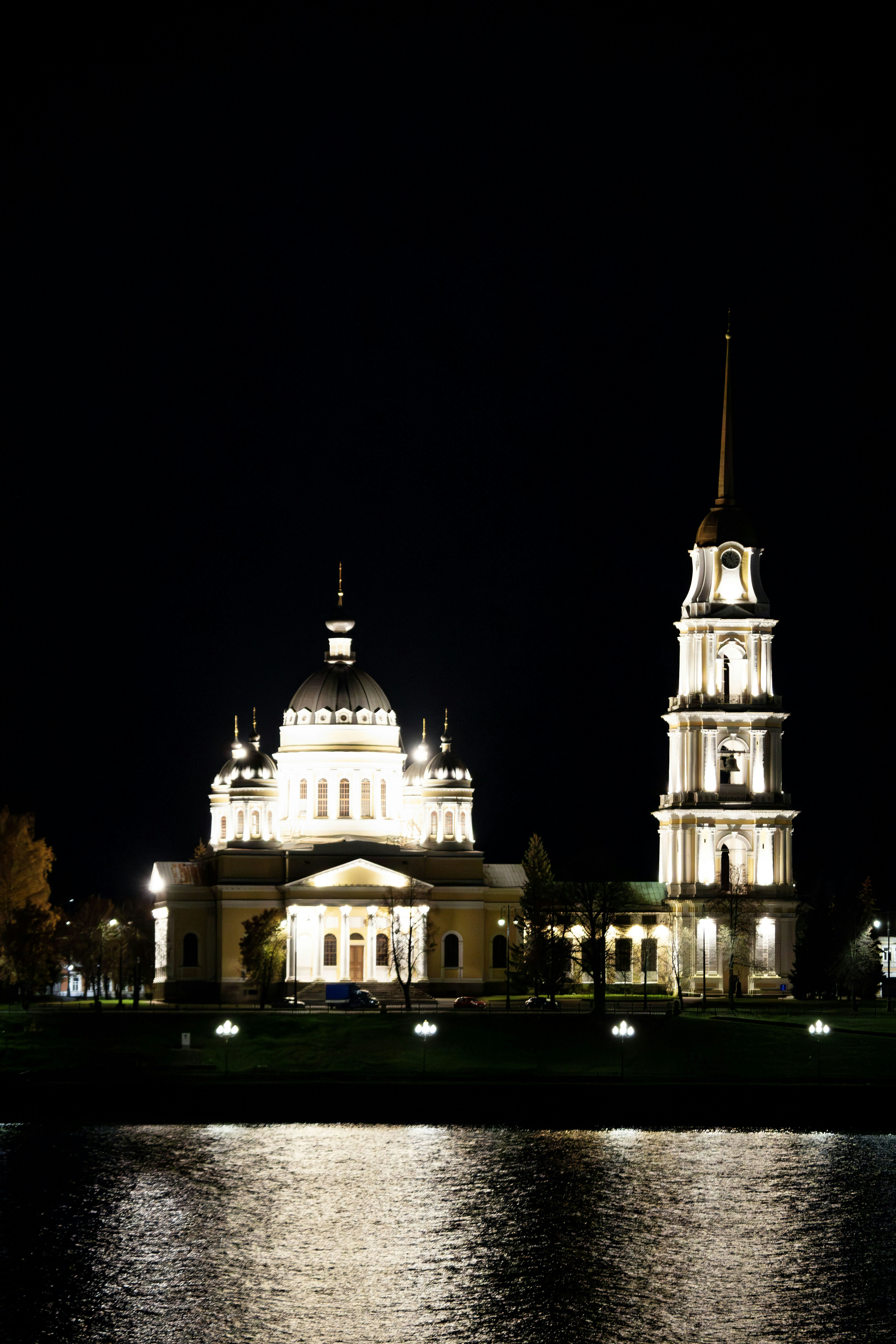 Riverside Cathedral at Night: Torchlit Domes and Tower Over Quiet Water