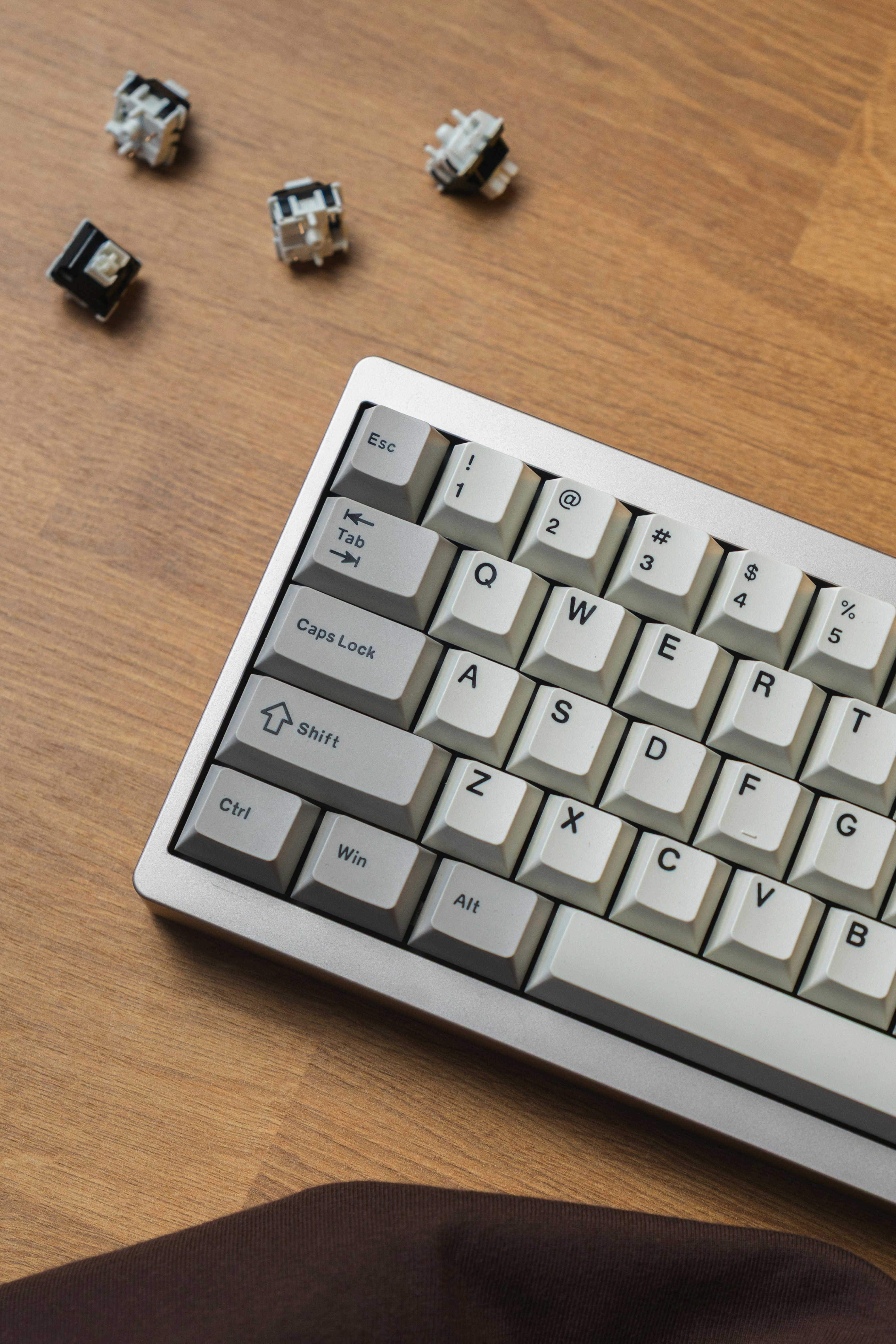 Beige Keycaps with Scattered Switches on a Wooden Desk