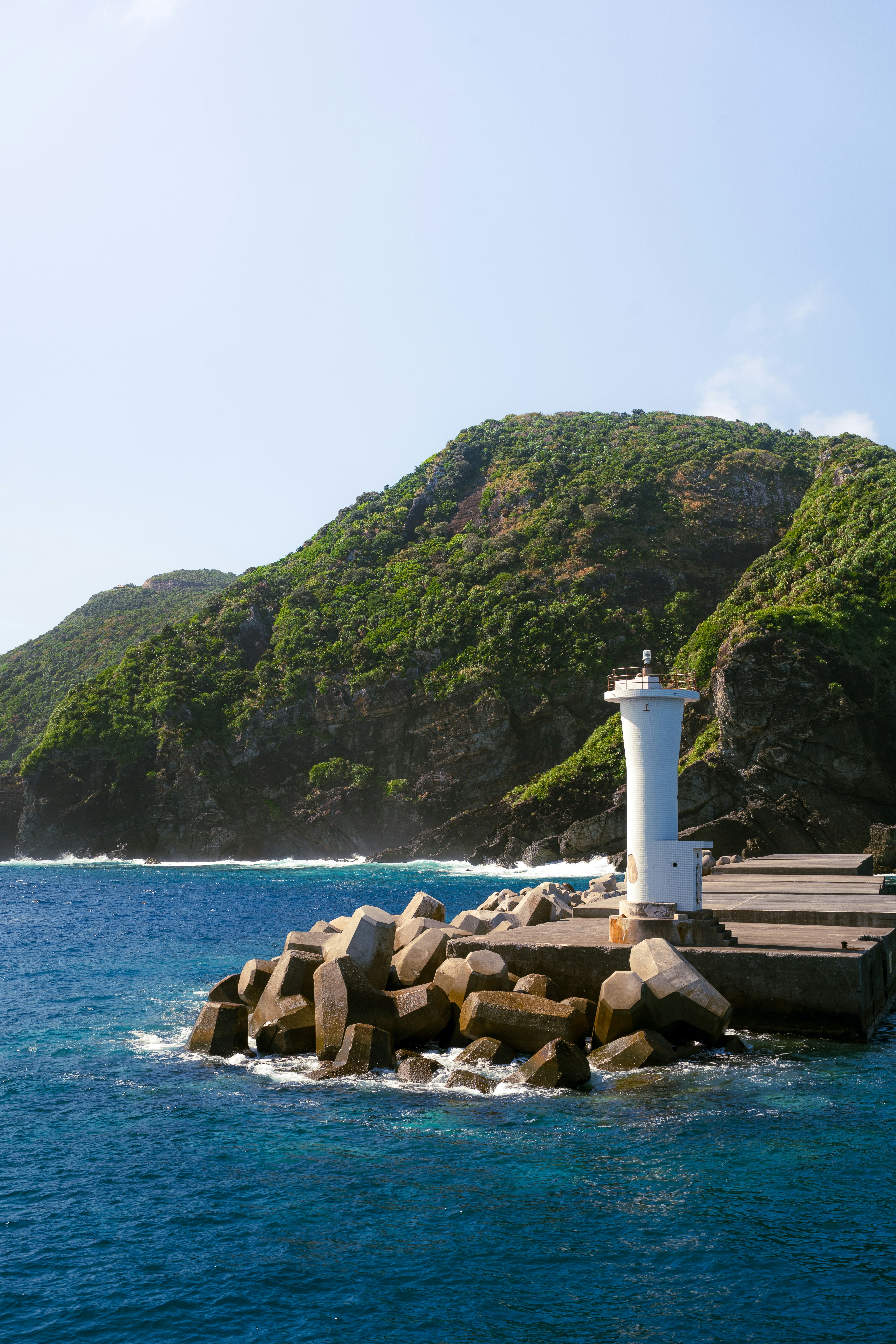 Lighthouse on the Breakwater Framing a Blue Sea and Emerald Cliff