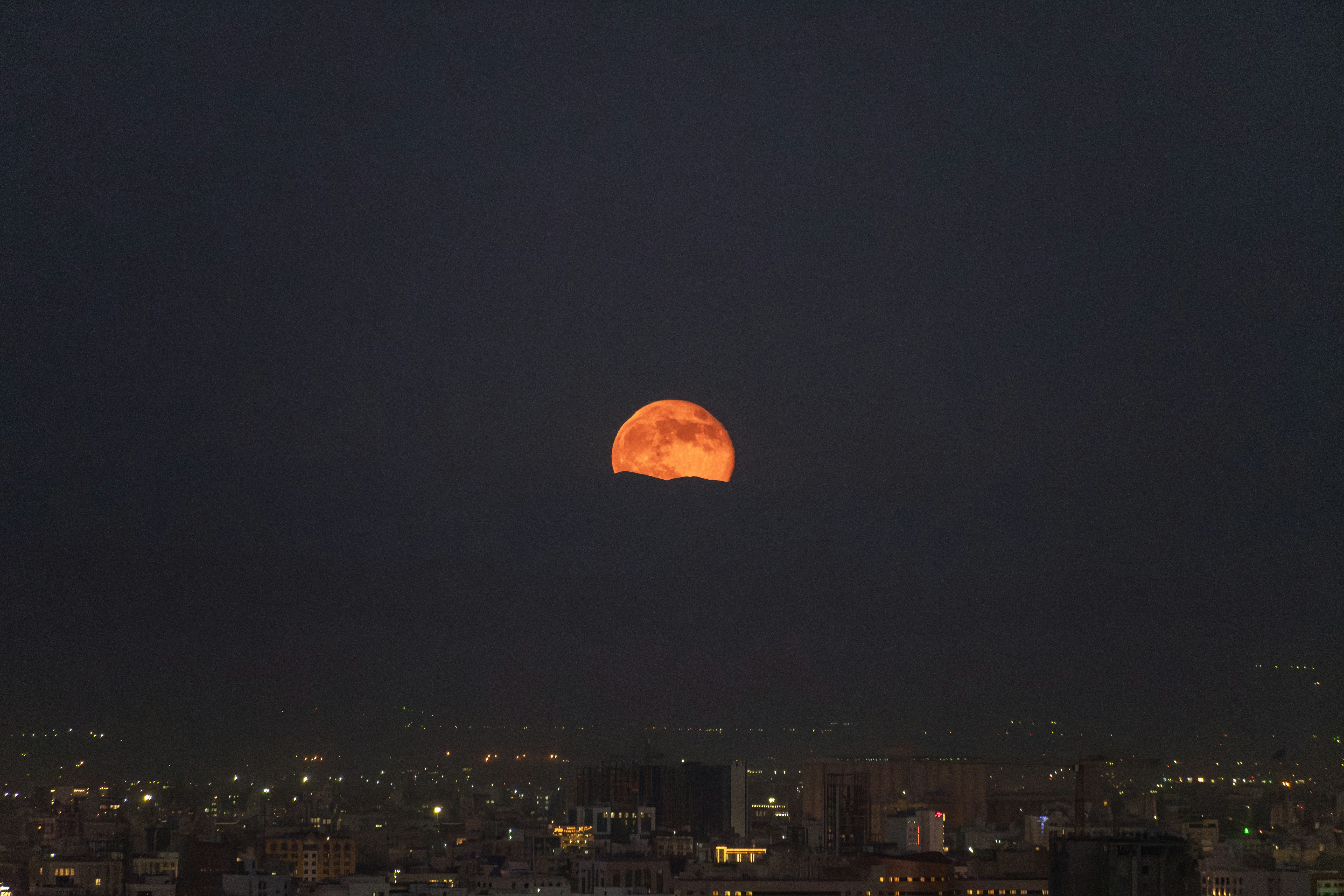Crimson Moonrise Over a Quiet City Skyline