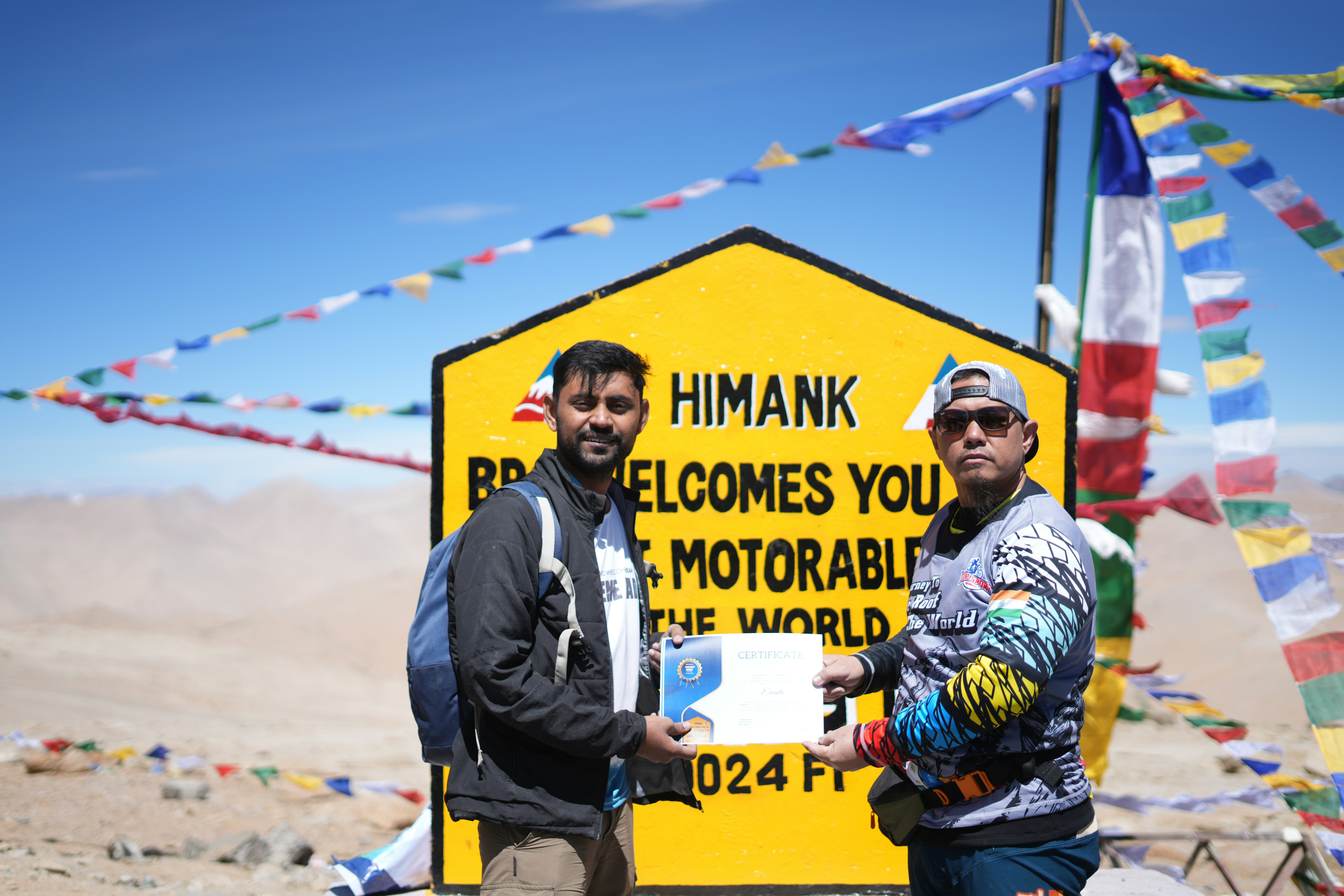 Handshake at the Himank Welcome Sign on a Windswept Himalayan Pass