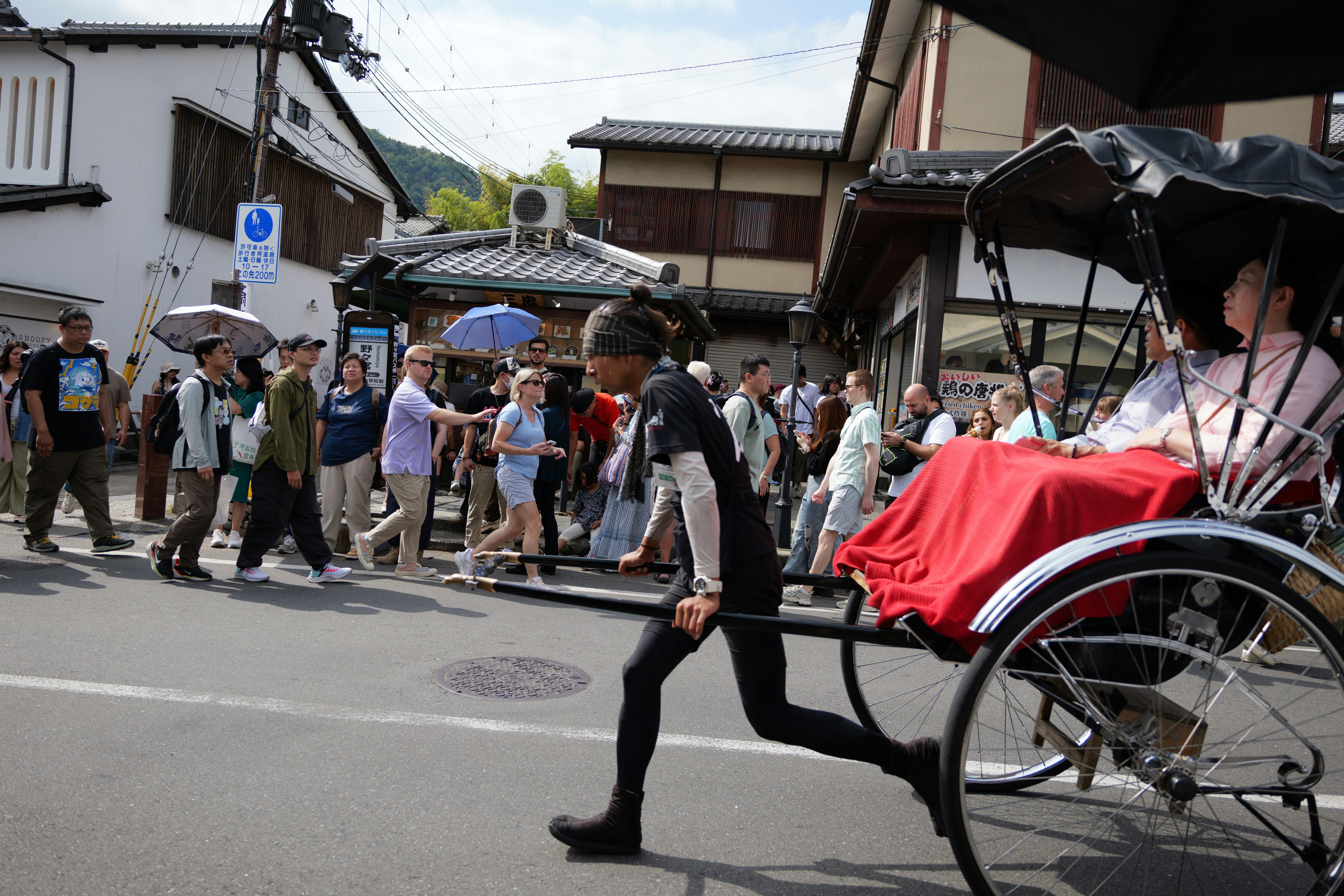 Rikshaw Run: A Black-Clad Runner Propels a Scarlet Cart Through a Busy Street