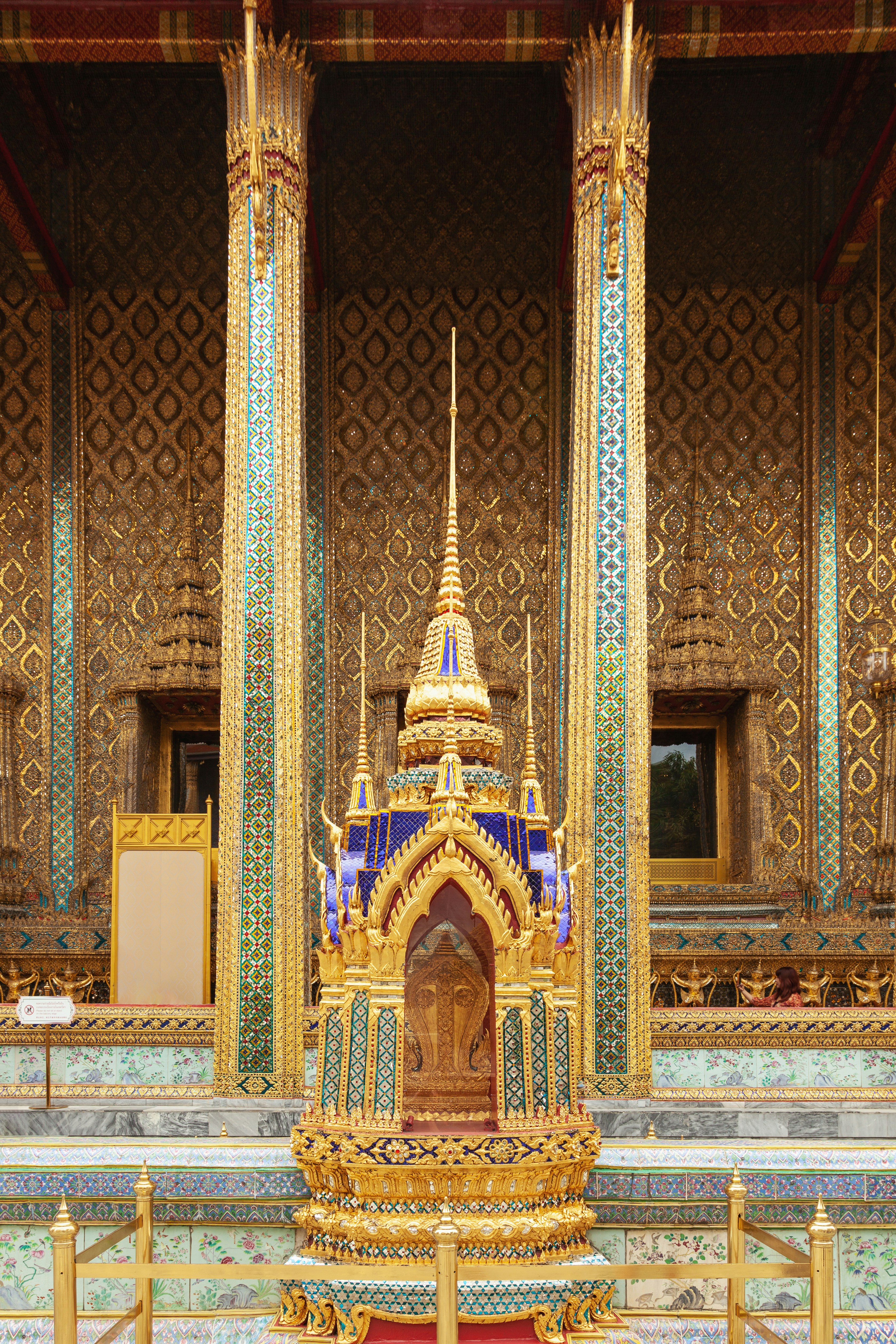 Gilded Spire Framed by Mosaic Columns in a Thai Temple Interior