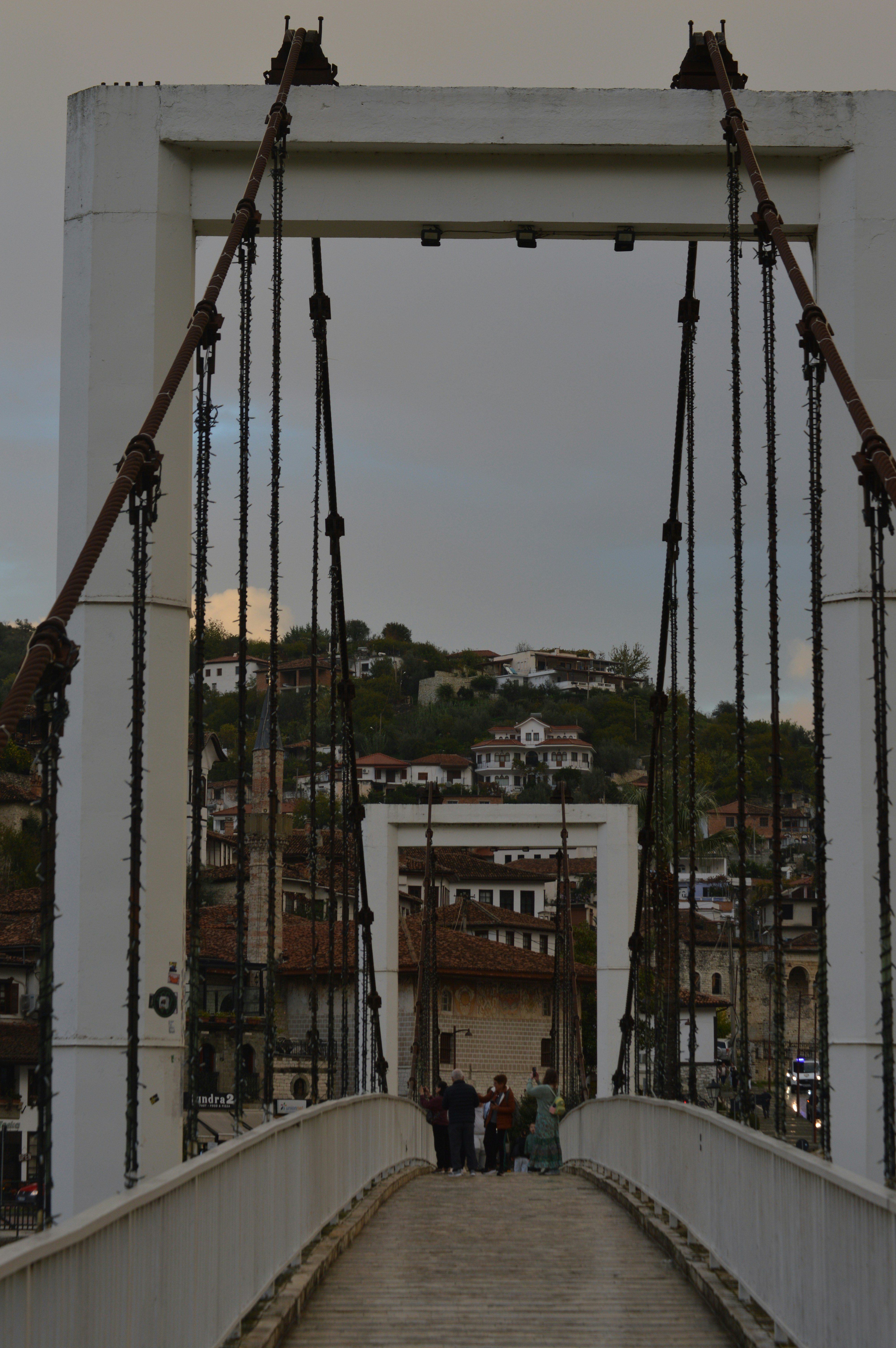 Midspan Convergence: White Suspension Bridge Framing a Hillside Town