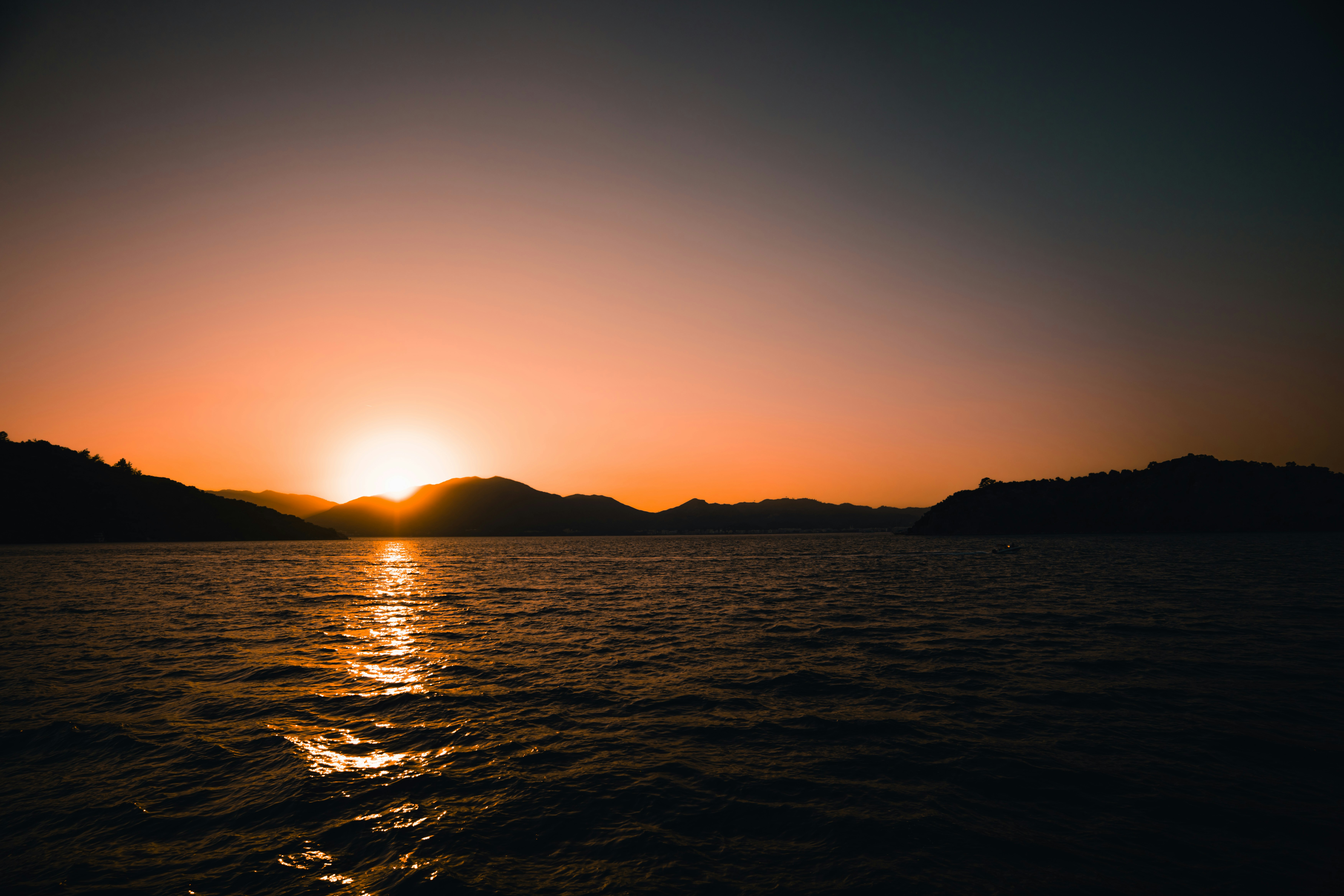 Sunset over a calm ocean with distant hills photo – Free Travel Image ...