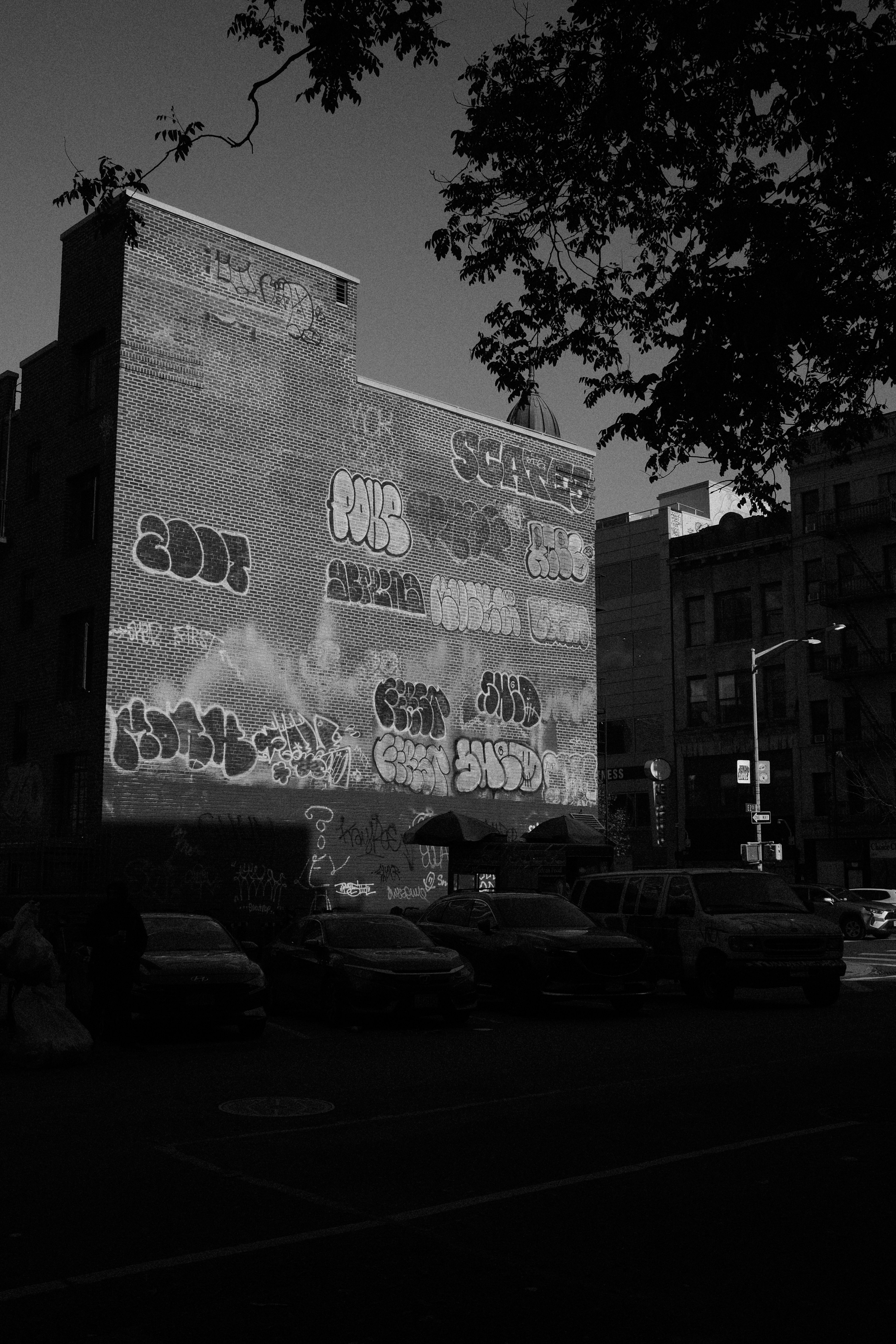 Monochrome Brick Canvas: A Graffiti Facade Under City Shadow