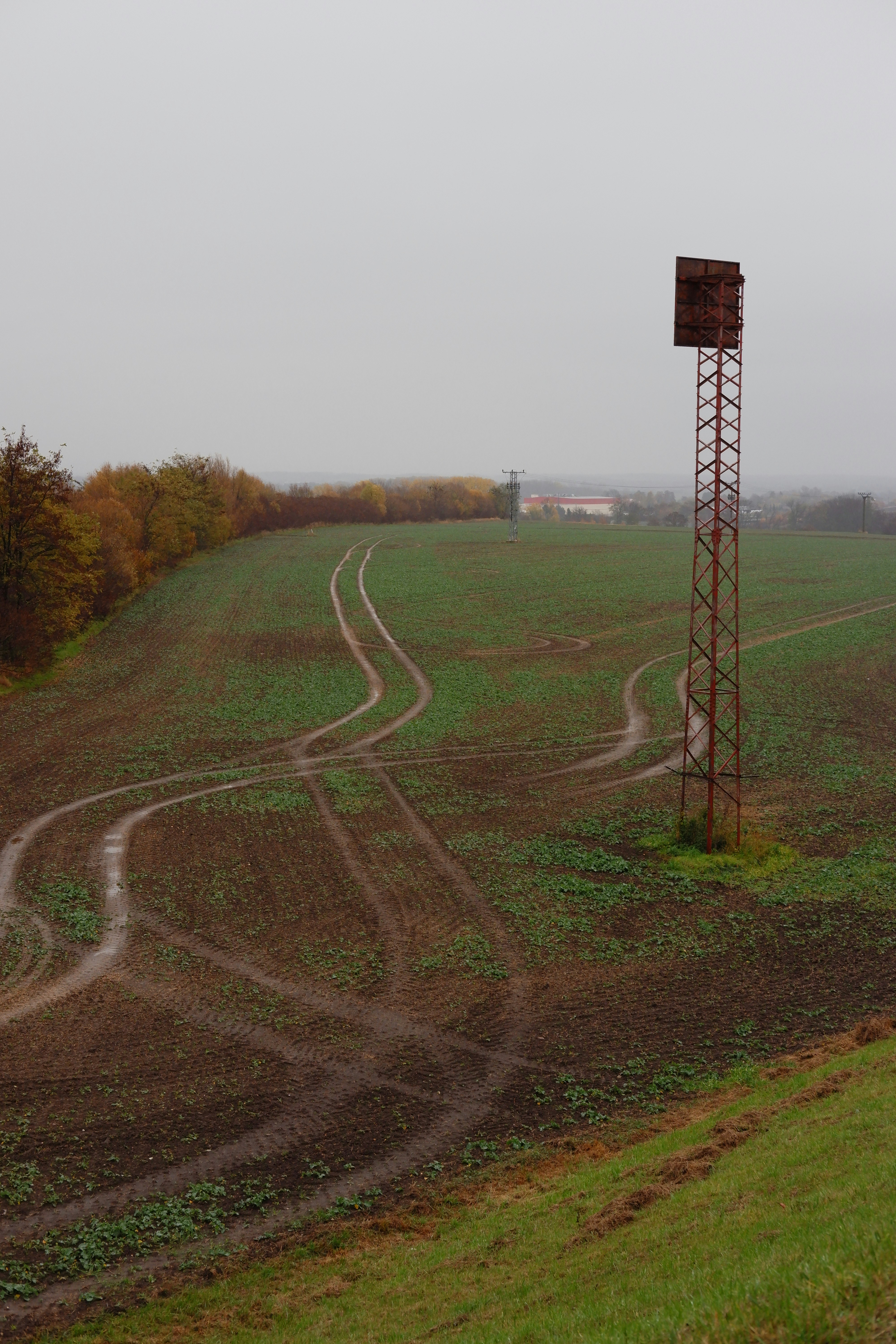 Iron Sentinel Over Mud-Slick Fields and Winding Tracks