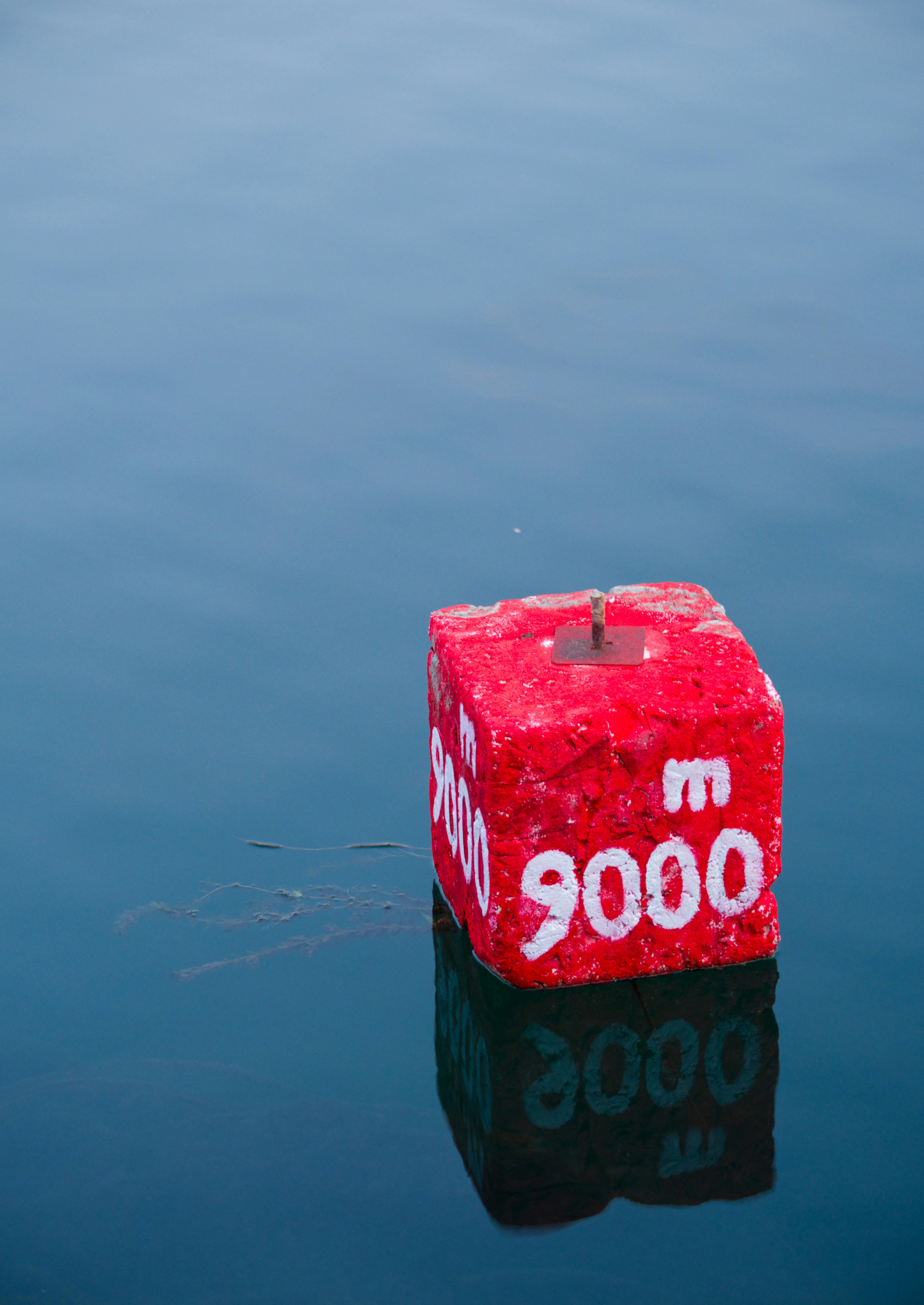 Crimson Cube Buoy Drifts Across a Glassy Blue Sea