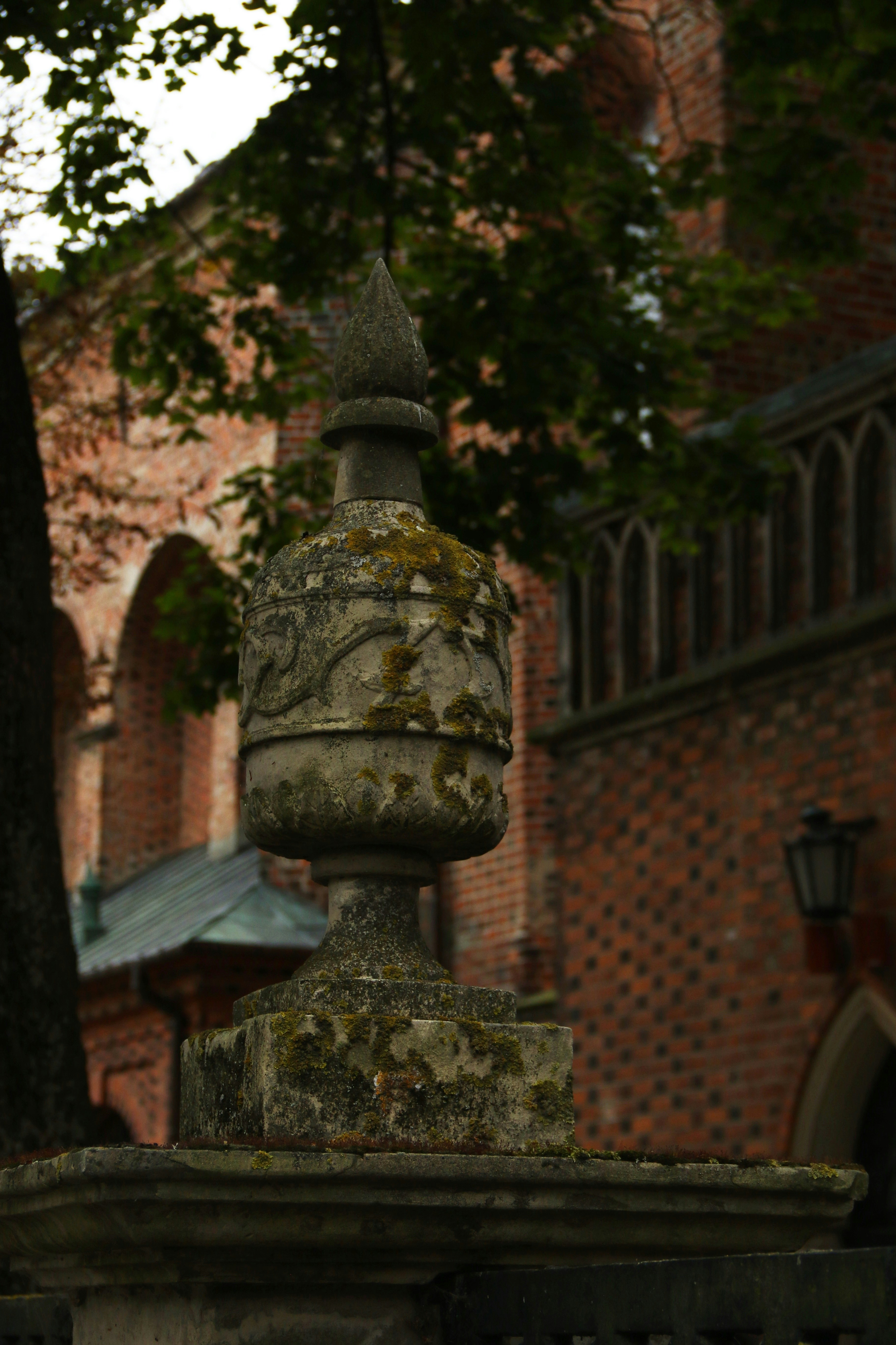 Moss-Covered Finial Framed by Red Brick Arches