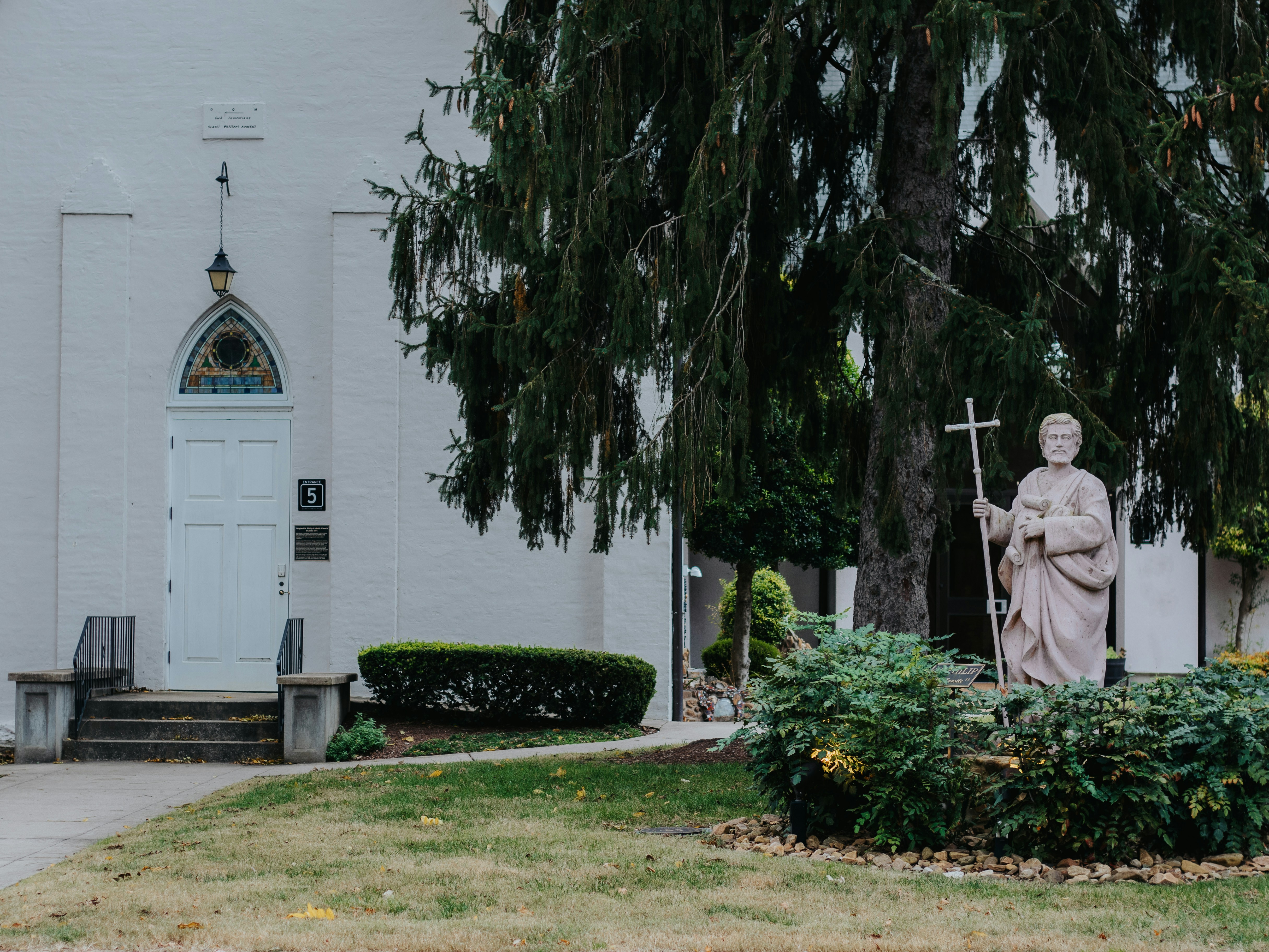 Stately Cross-Bearing Statue in a Tranquil White Chapel Courtyard