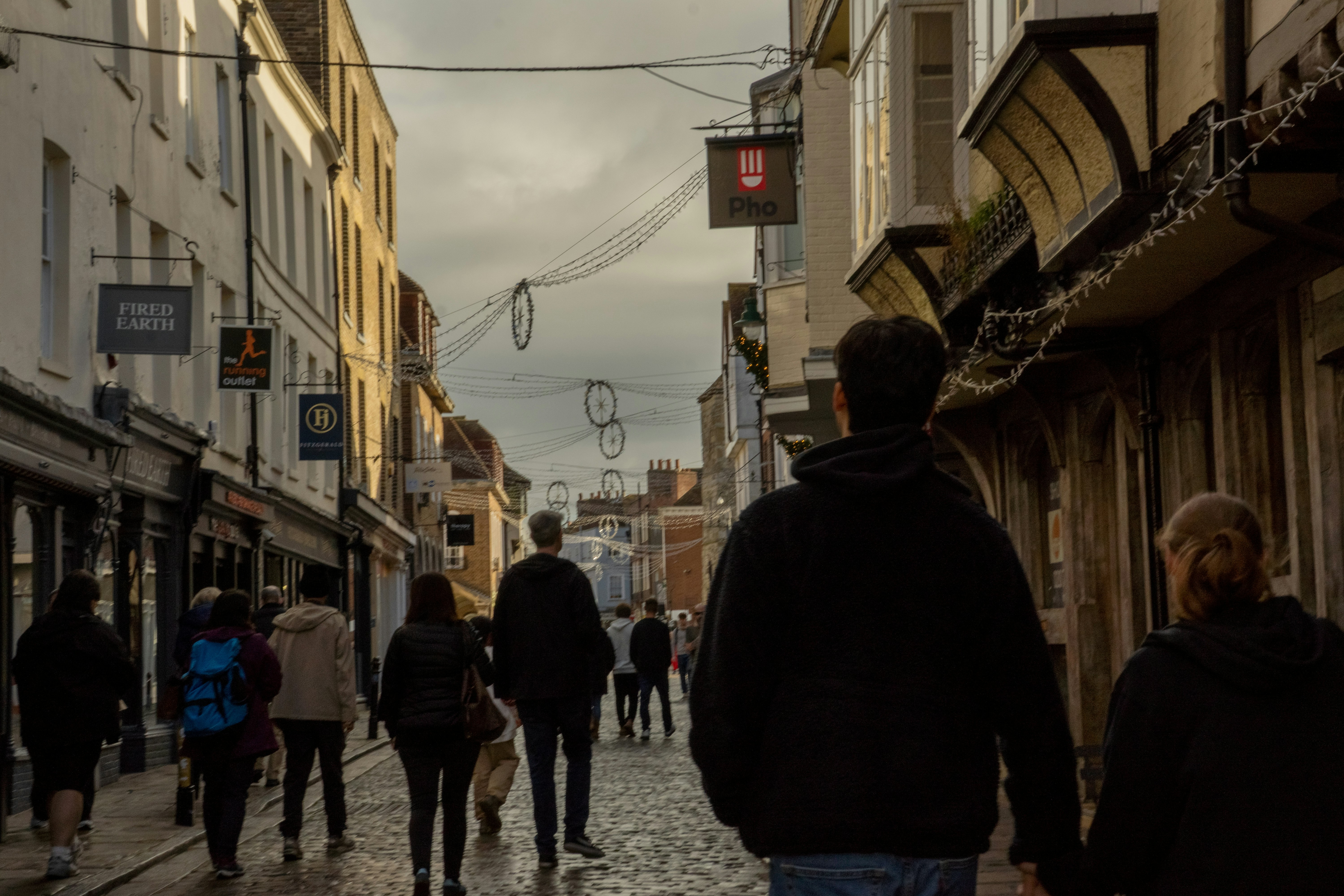 Hooded Silhouette at the End of a Festooned Cobblestone Street