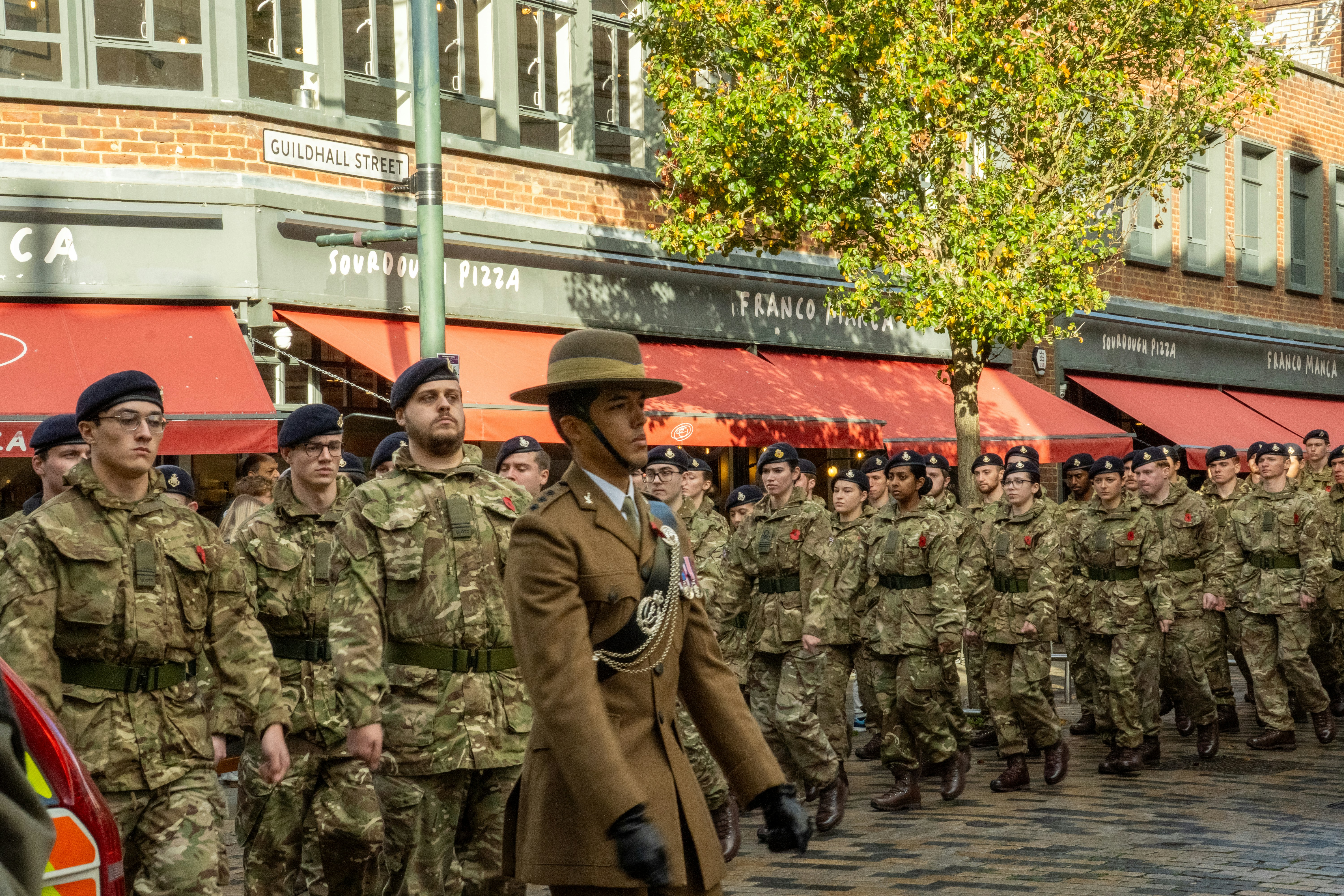 Column of soldiers marches down a city street during Remembrance Sunday parade.