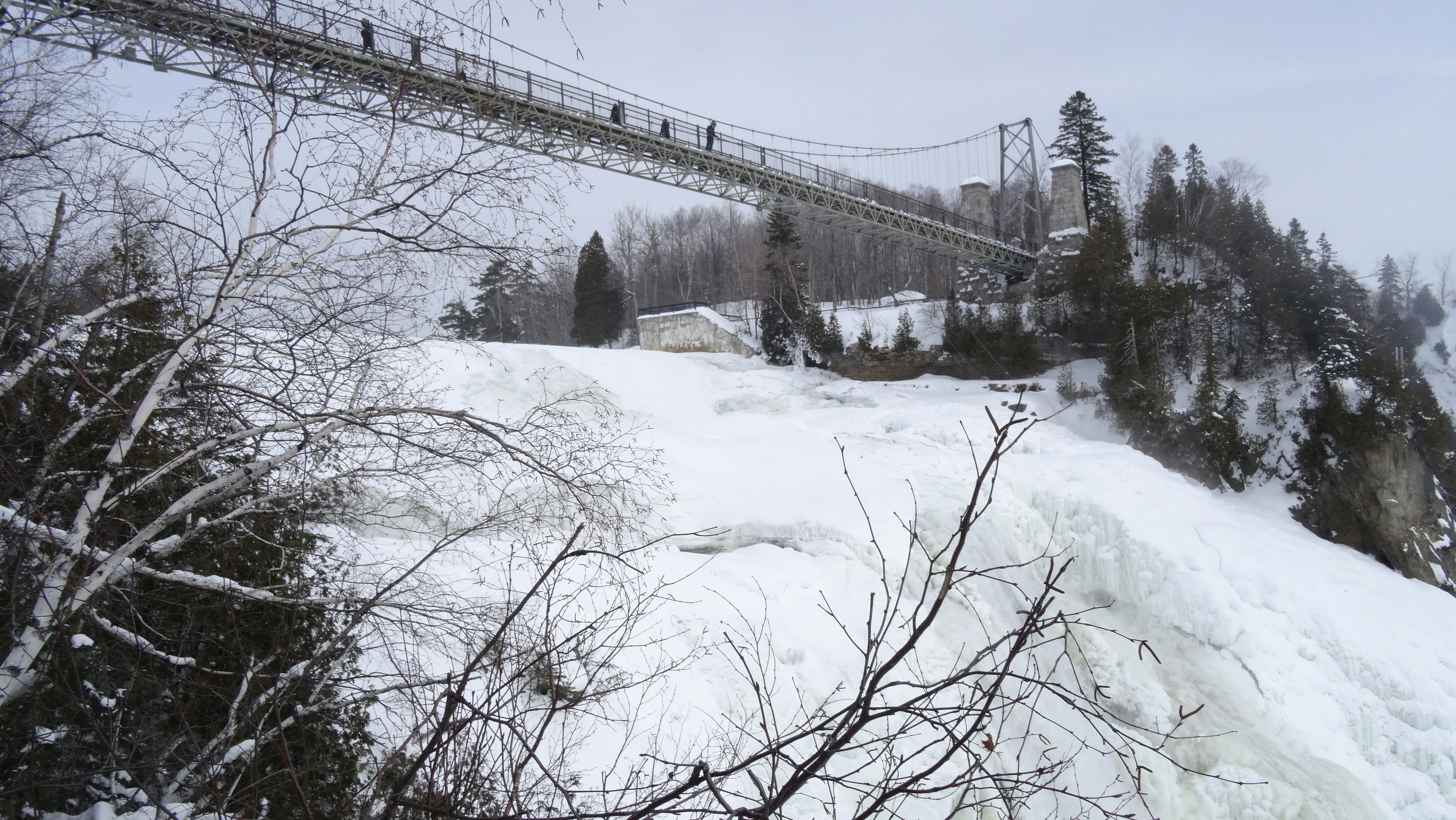 Suspension bridge over a frozen waterfall in winter